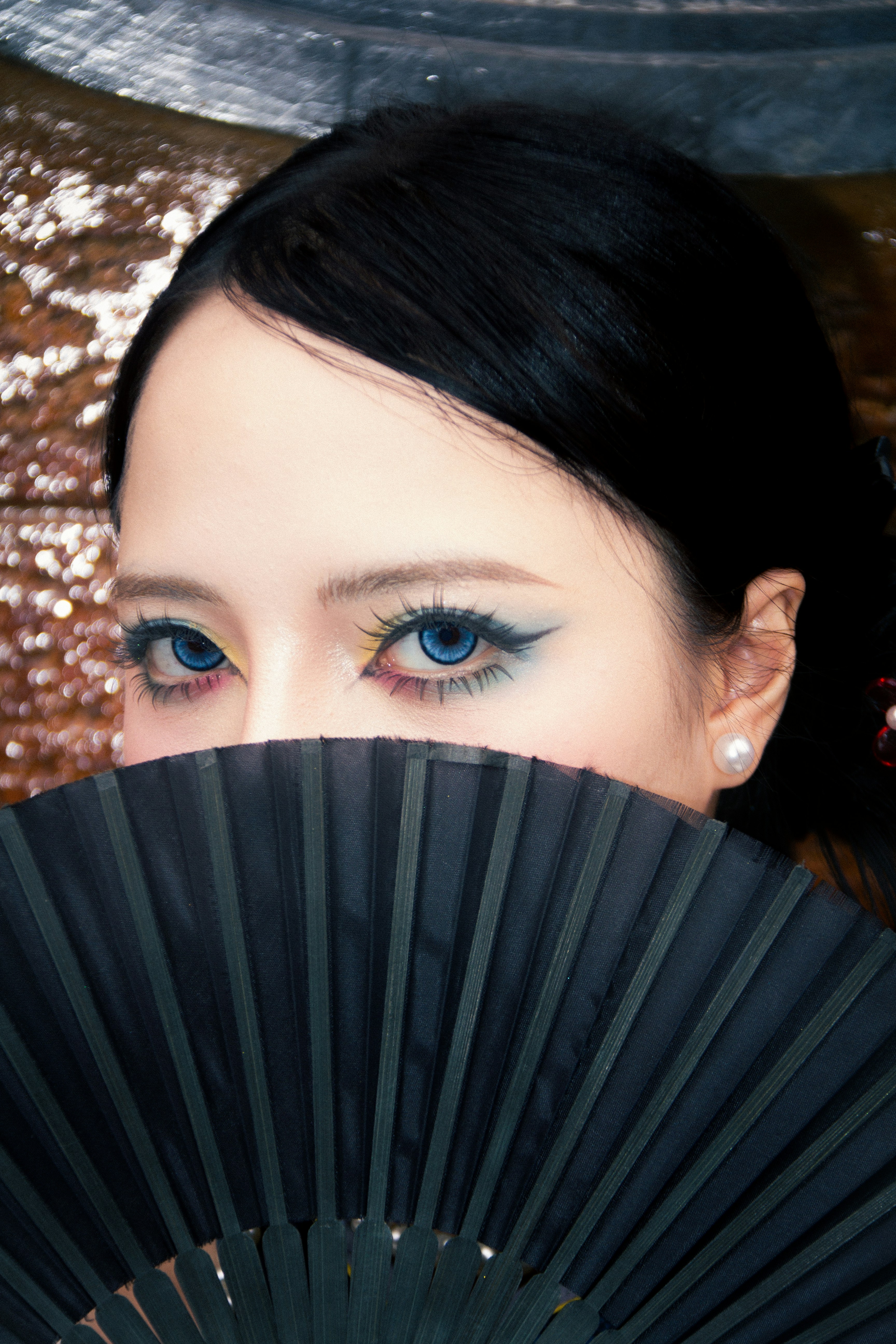 Woman with blue eyes holding a black fan