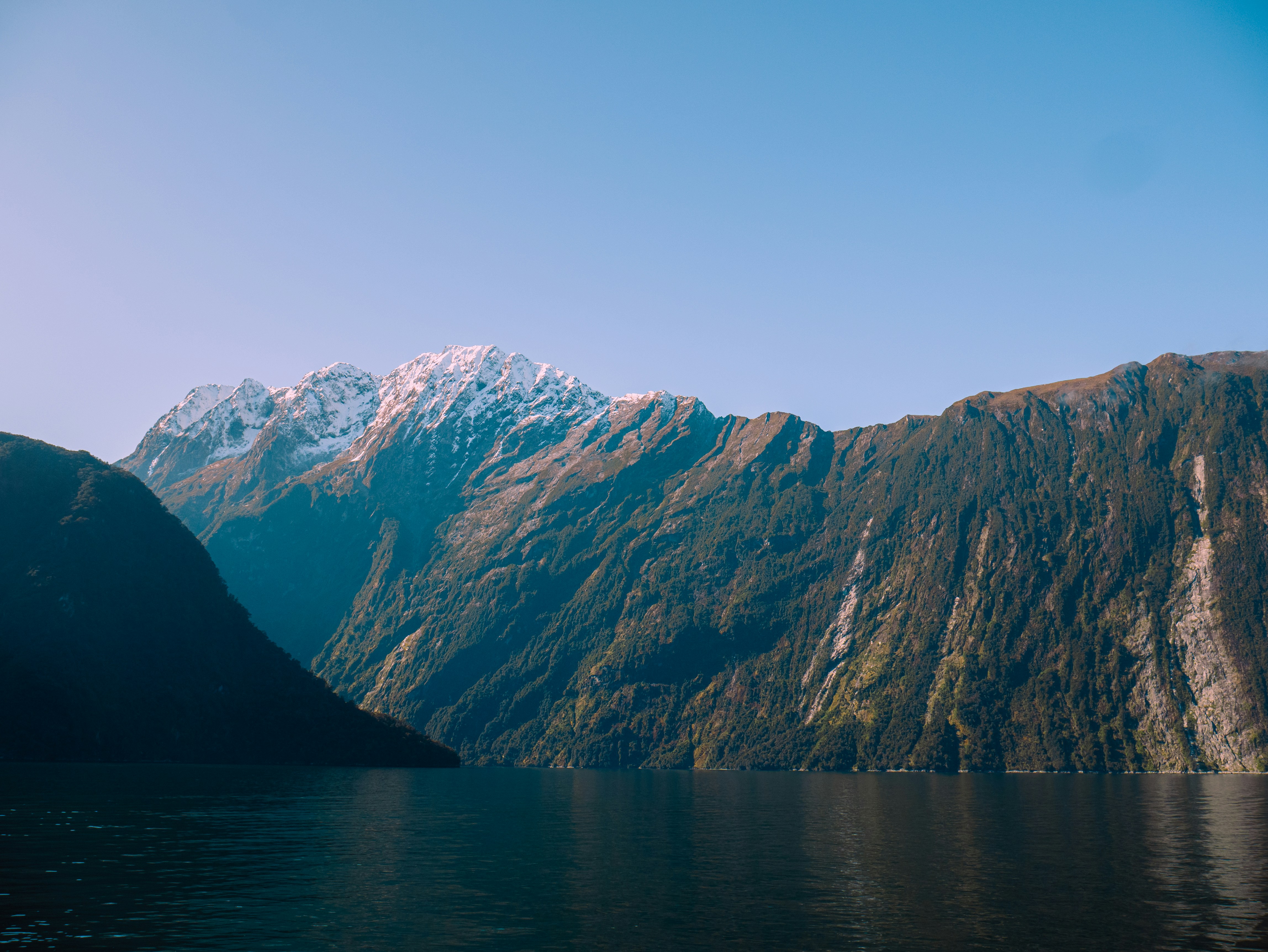 Snow-capped mountains rise above a calm lake.