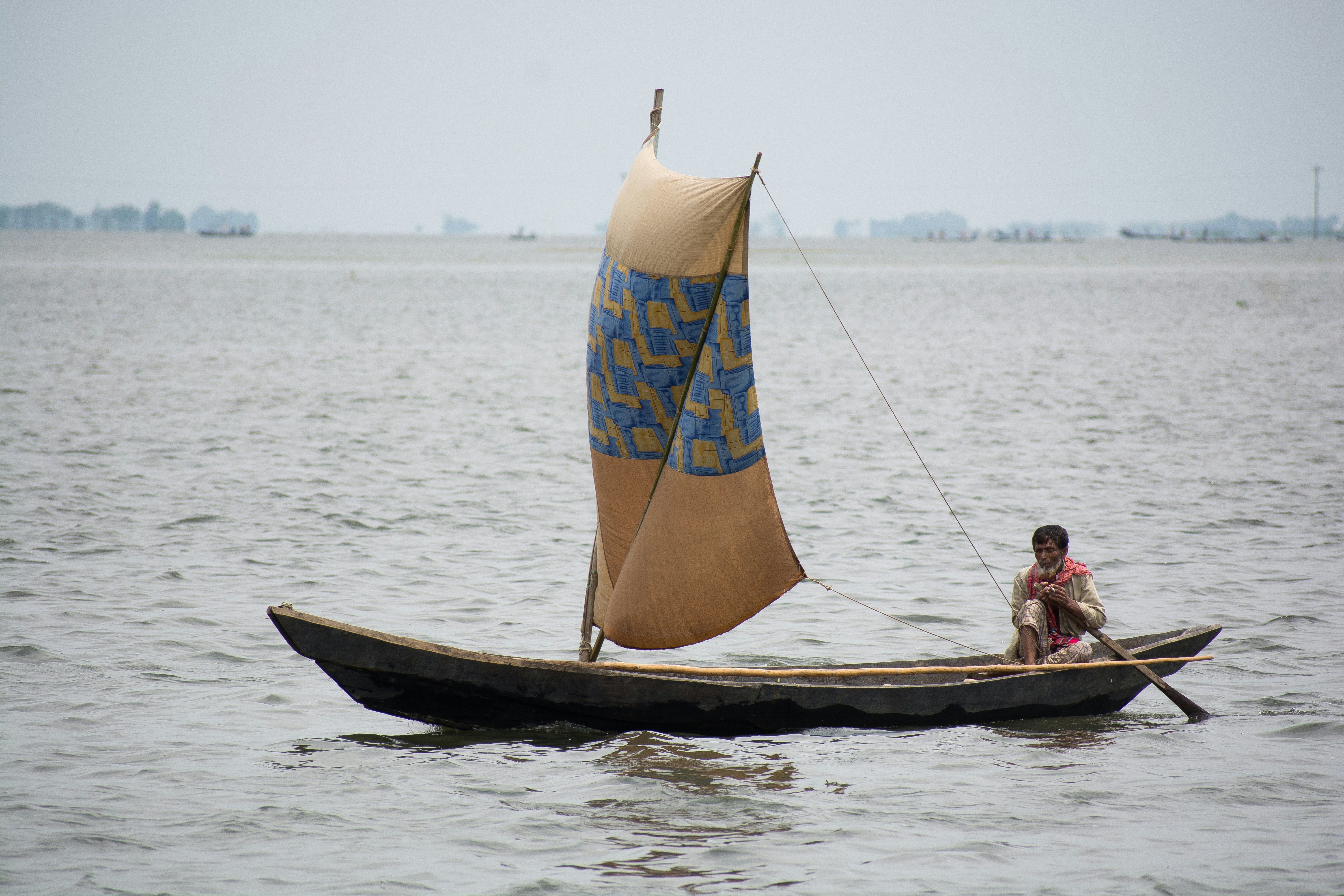 A person sails a small wooden boat on the water.