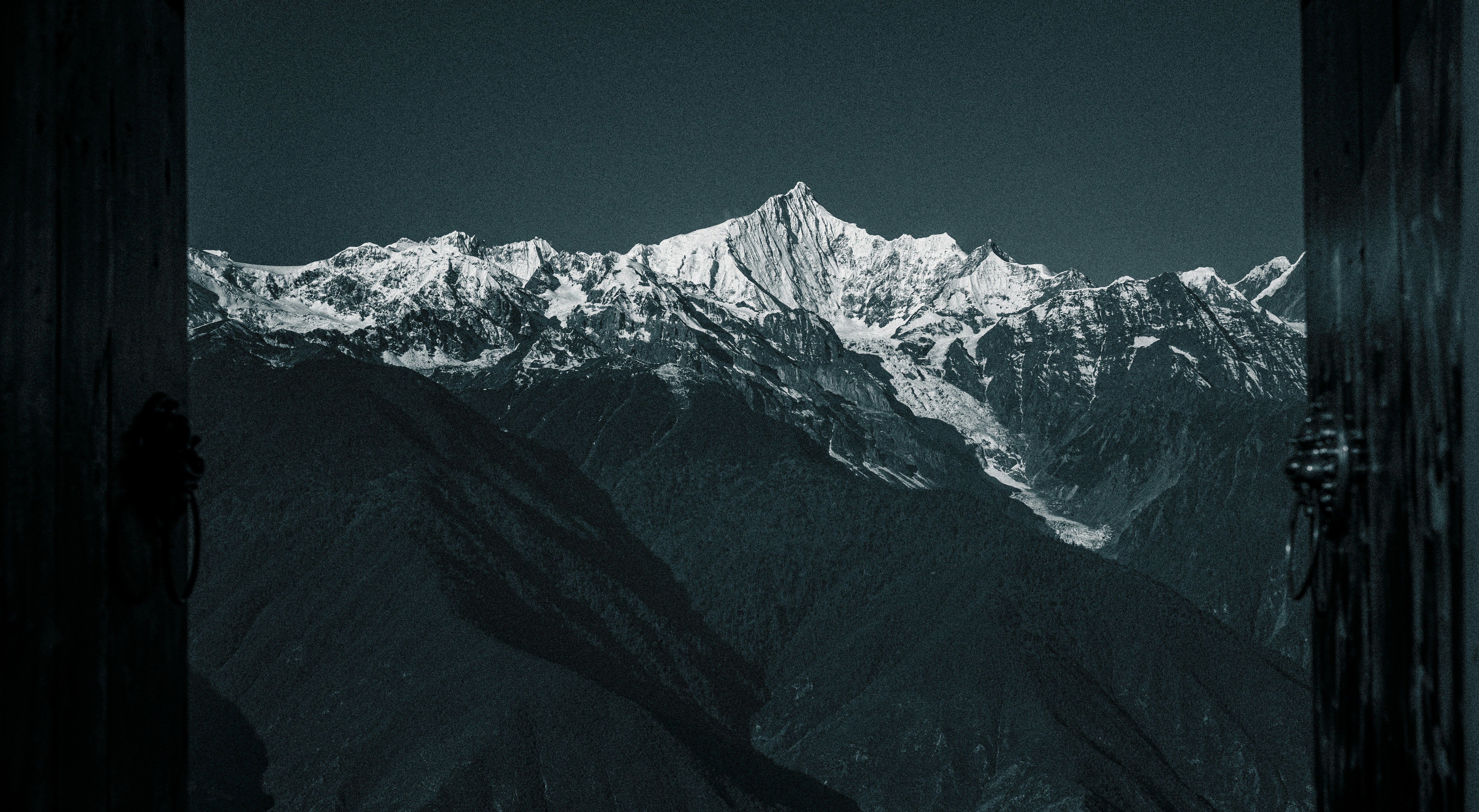 Snow Mountain Behind the Door | Snow-capped mountain range under a dark sky