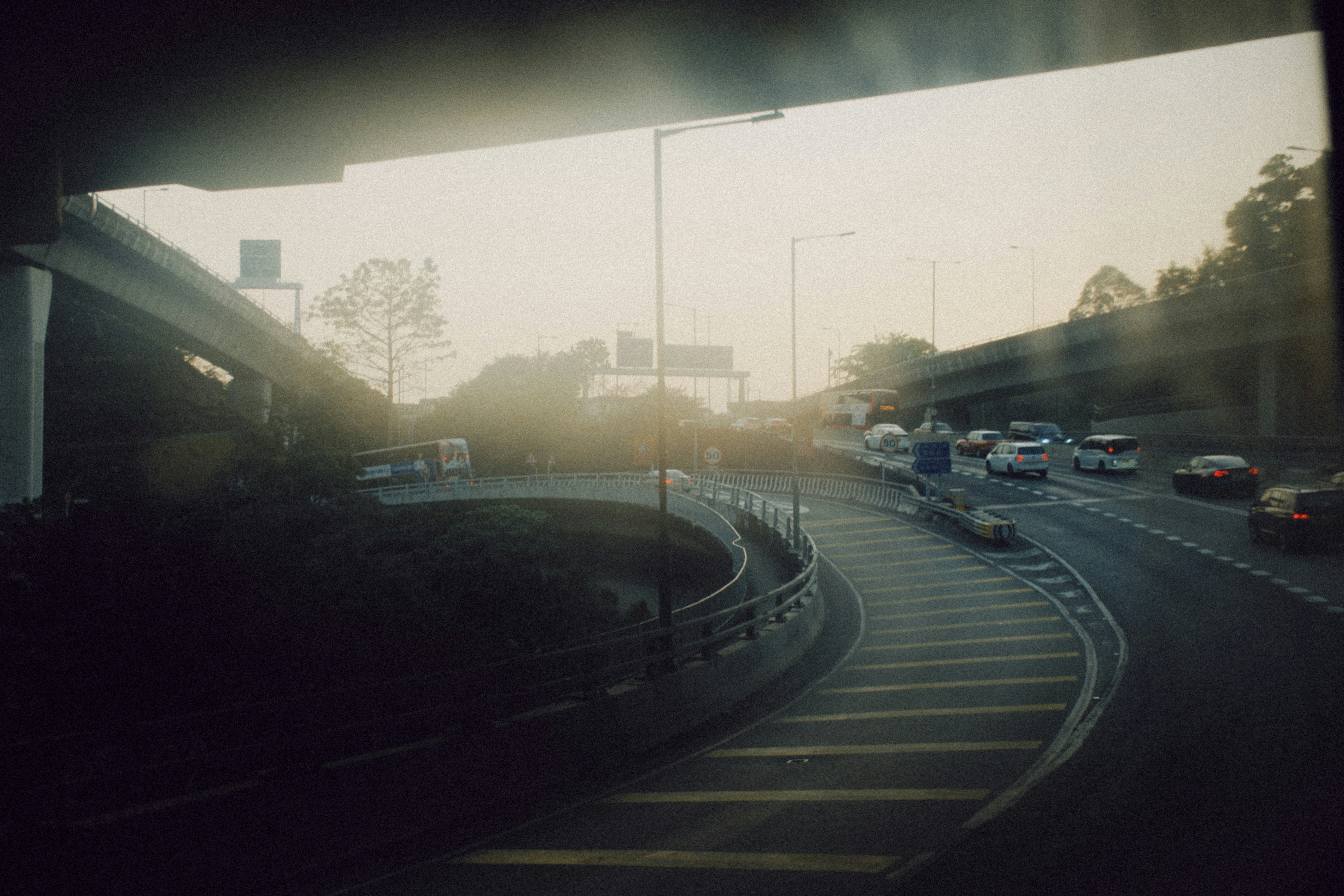 Cars driving on a highway interchange at dusk.