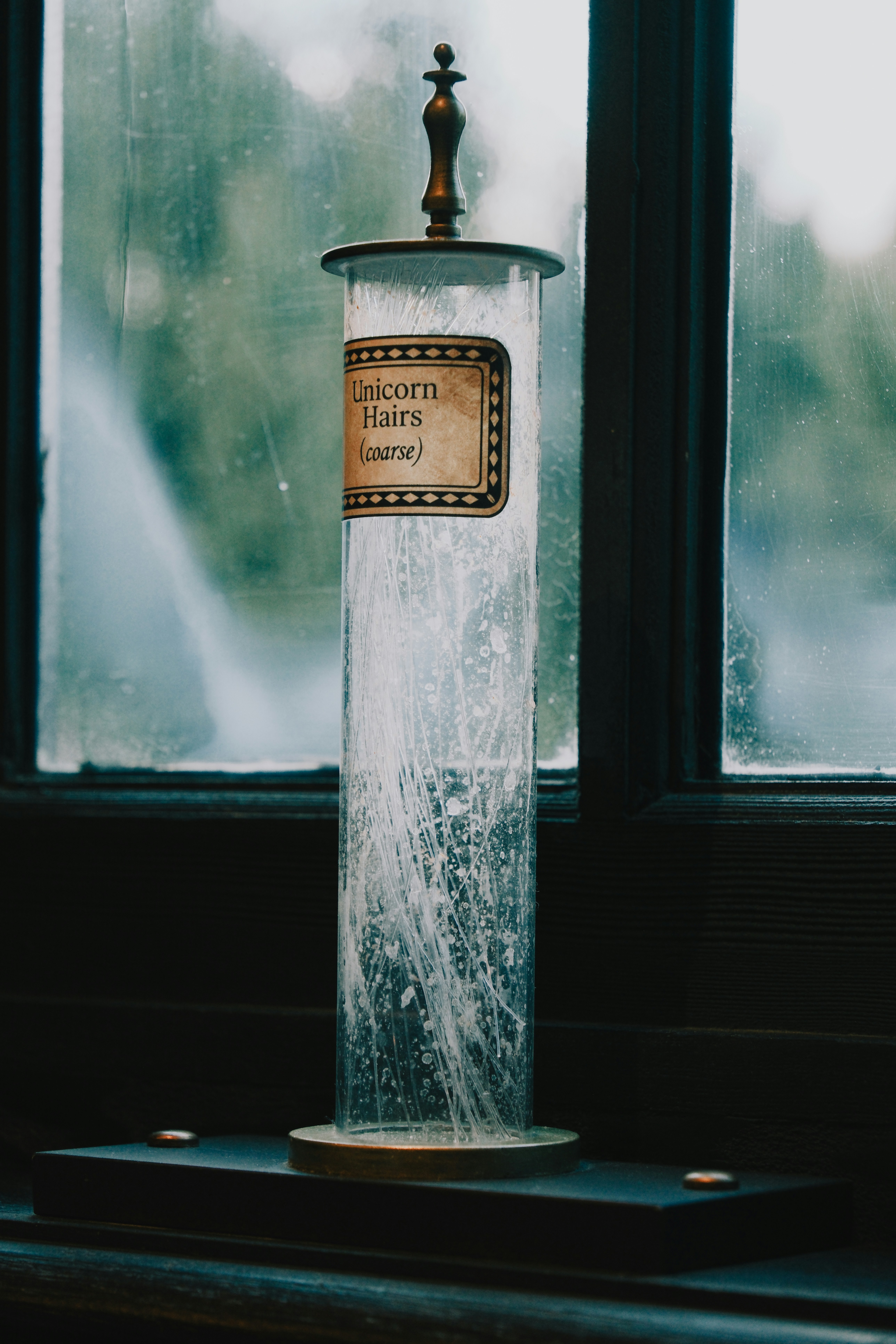 Glass cylinder with unicorn hairs on a shelf.