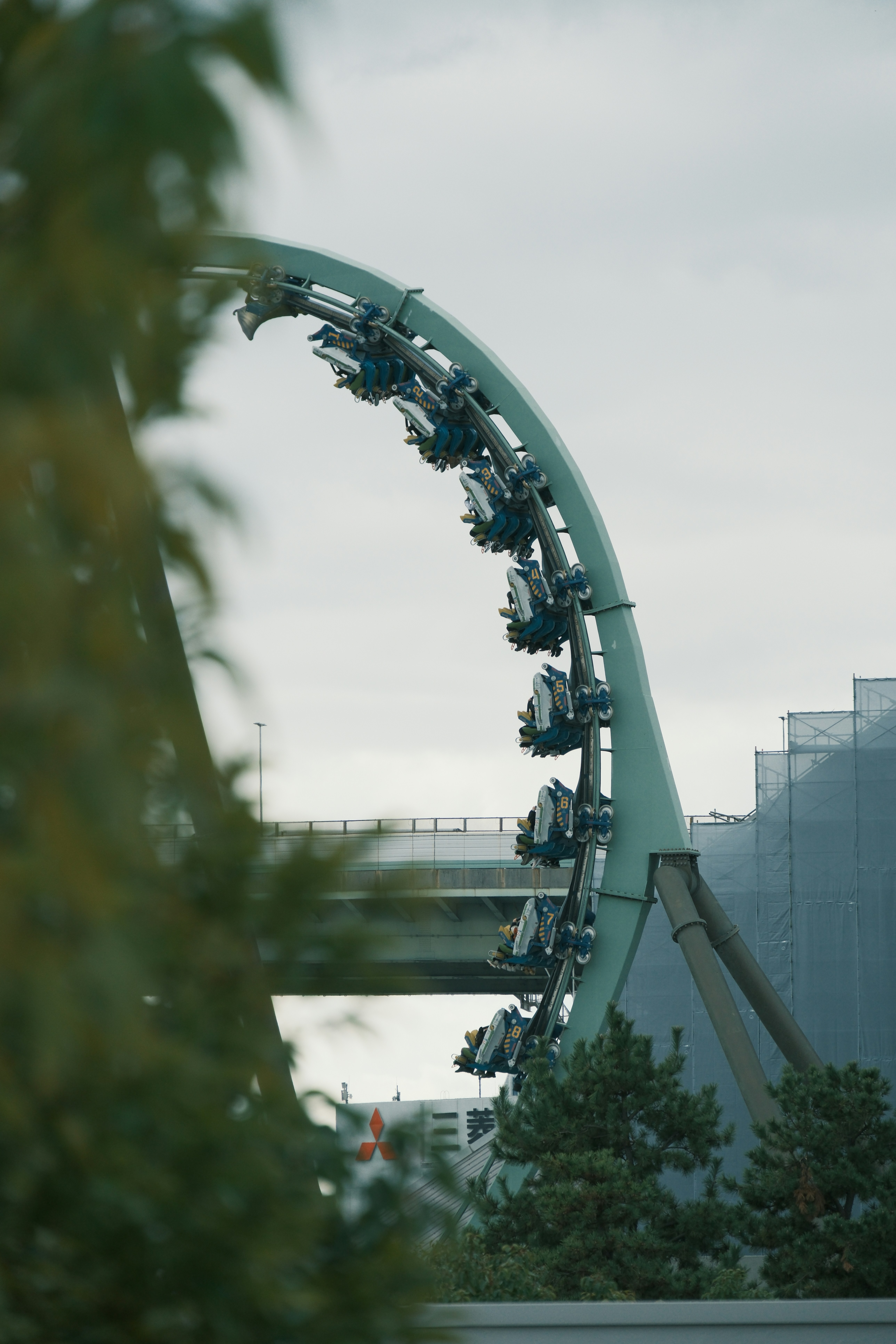 Roller coaster riders experiencing the thrill of a vertical loop against a cloudy sky.