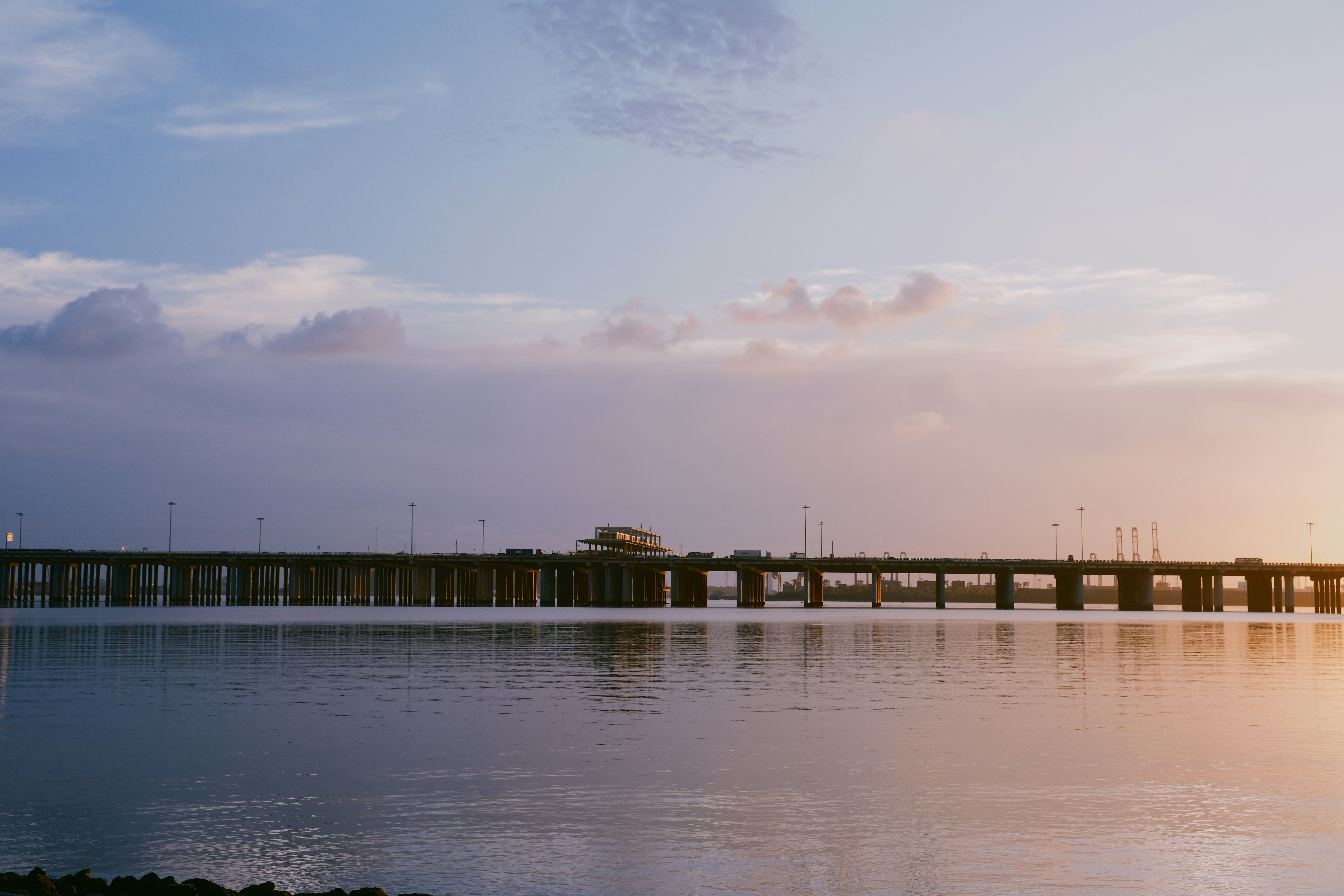 Long bridge over calm water at sunset
