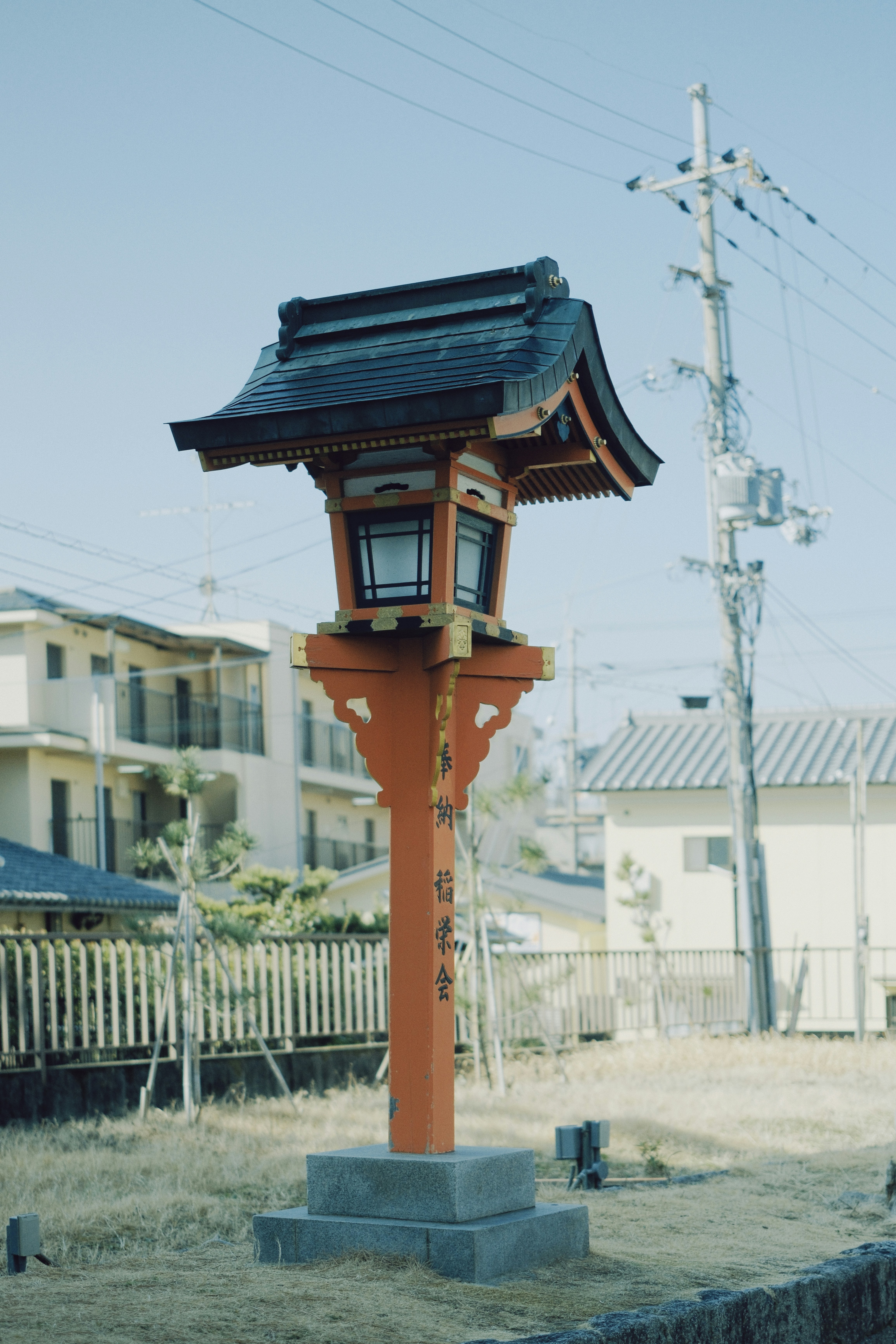 Shinto Lantern on an Orange Pedestal Stands Guard Over a Quiet Suburban Street
