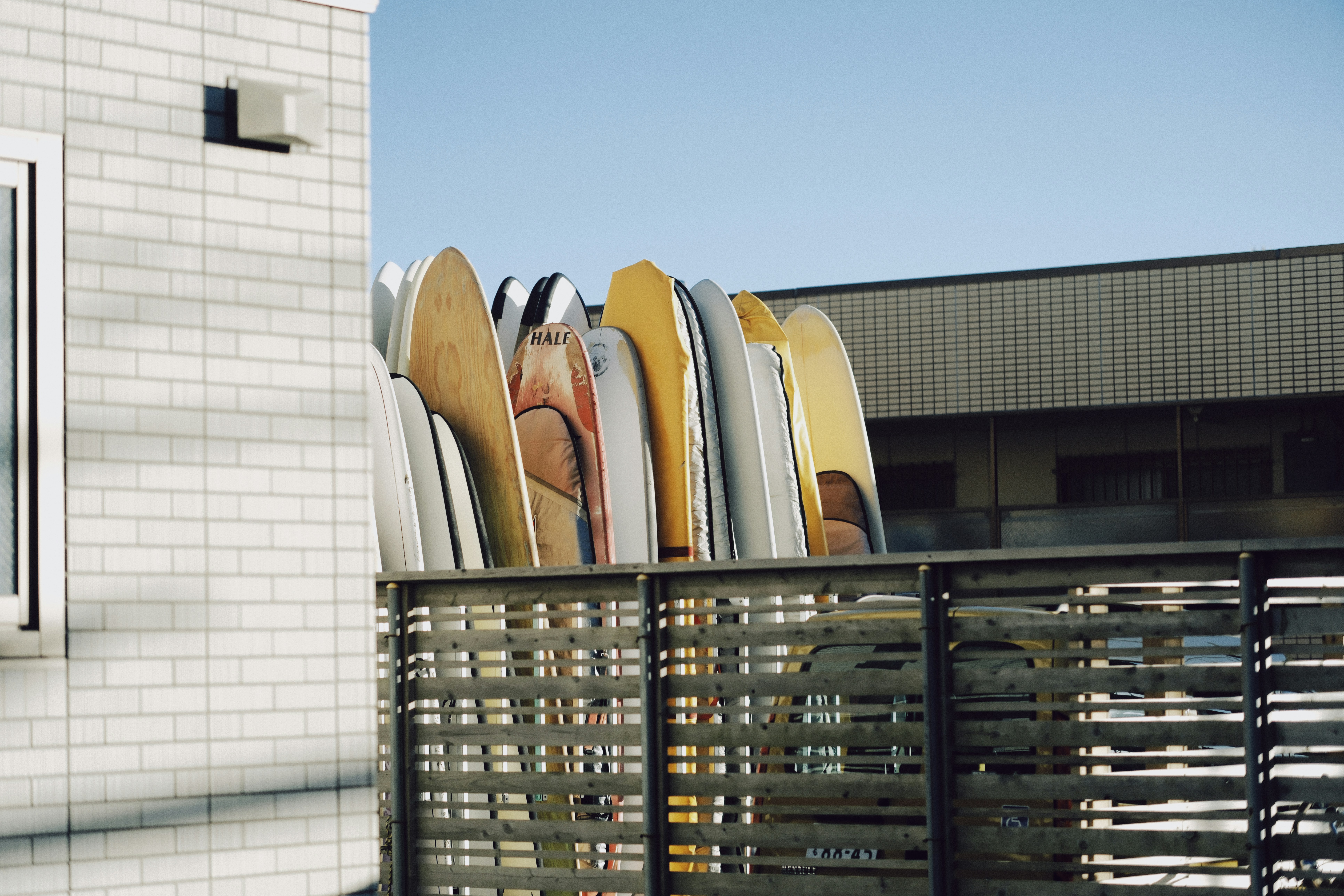 Surfboards stored upright behind a fence