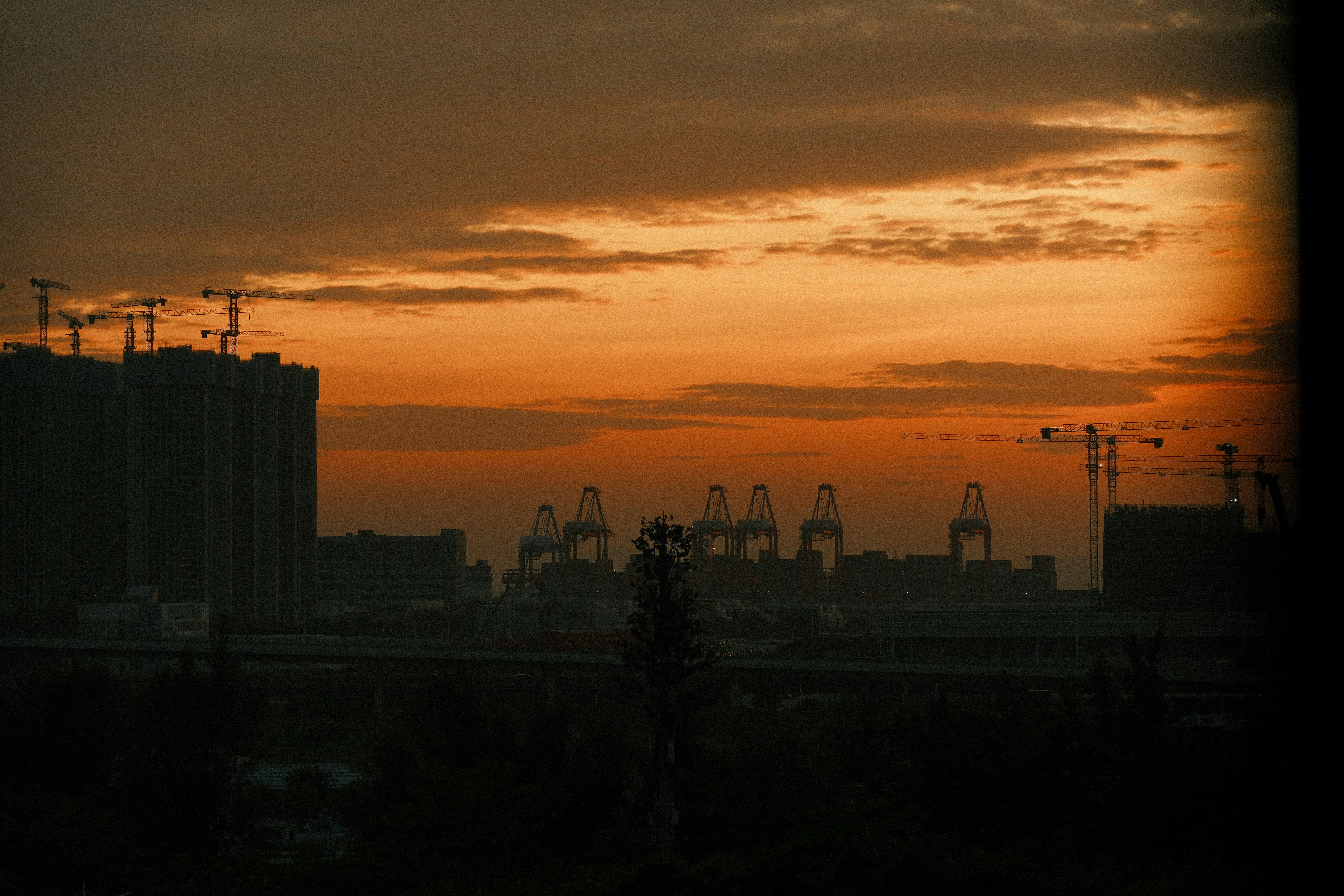 Sunset over industrial port with cranes and buildings