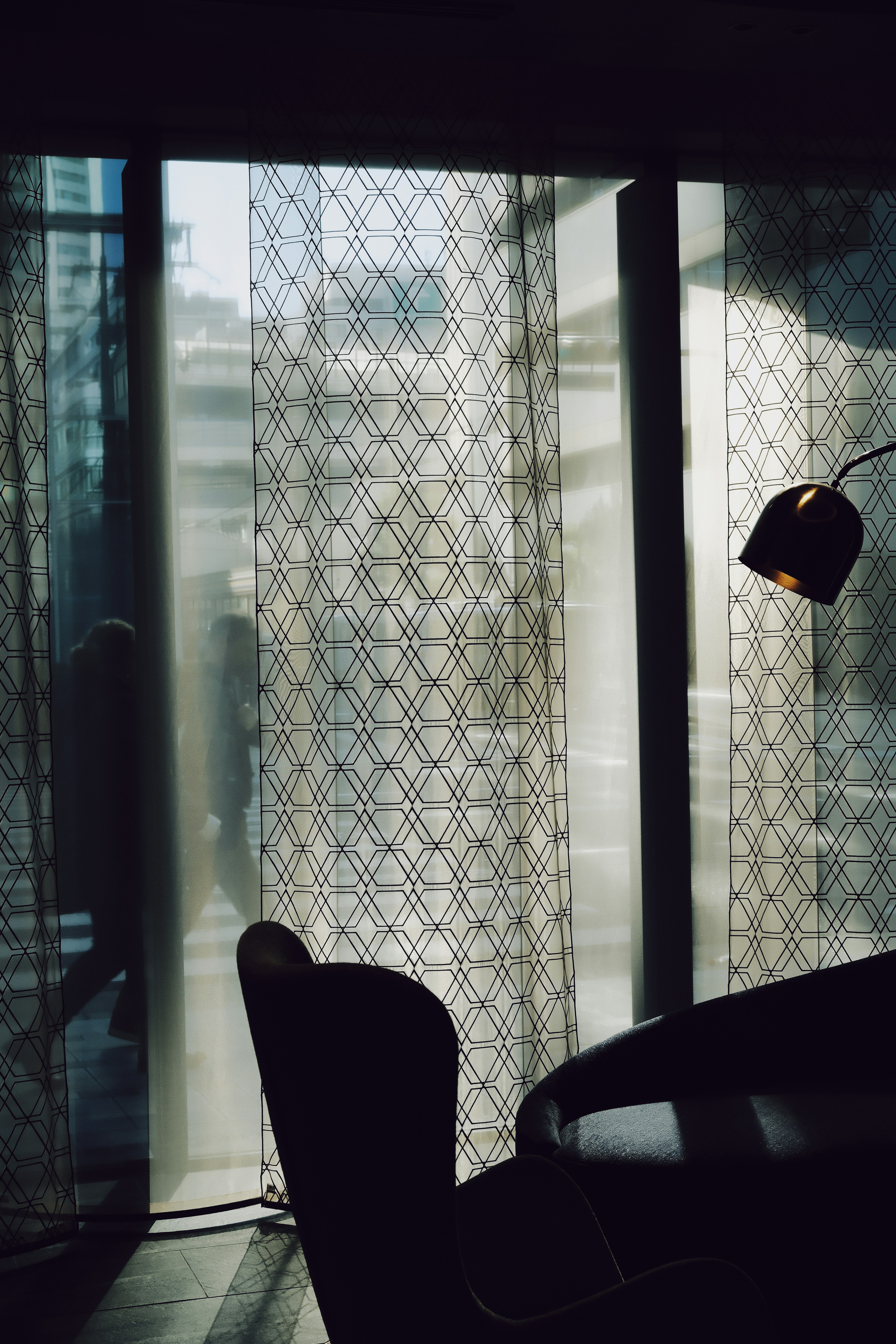 Armchair by window with patterned sheer curtains