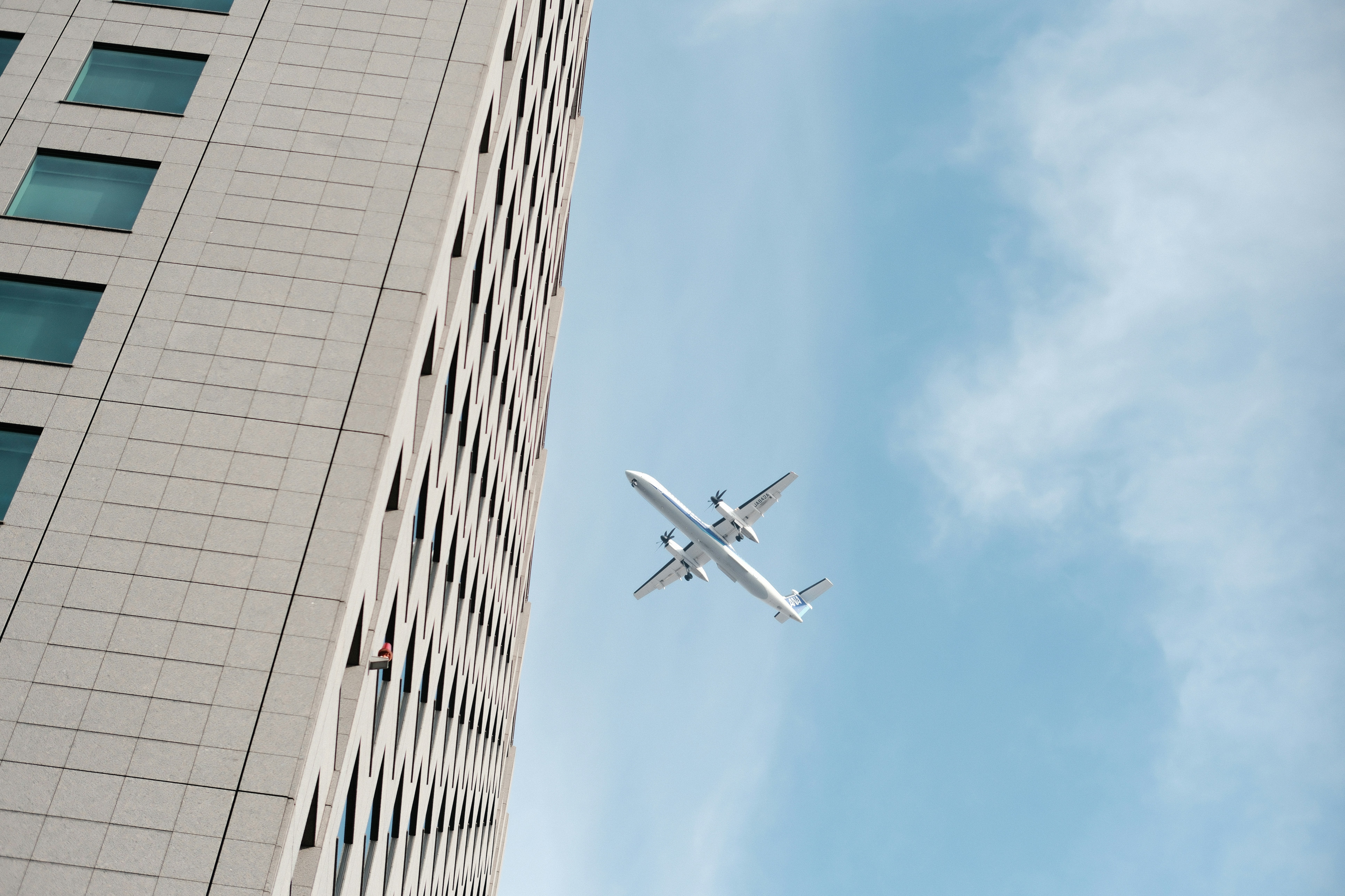 Airplane flying near a modern building
