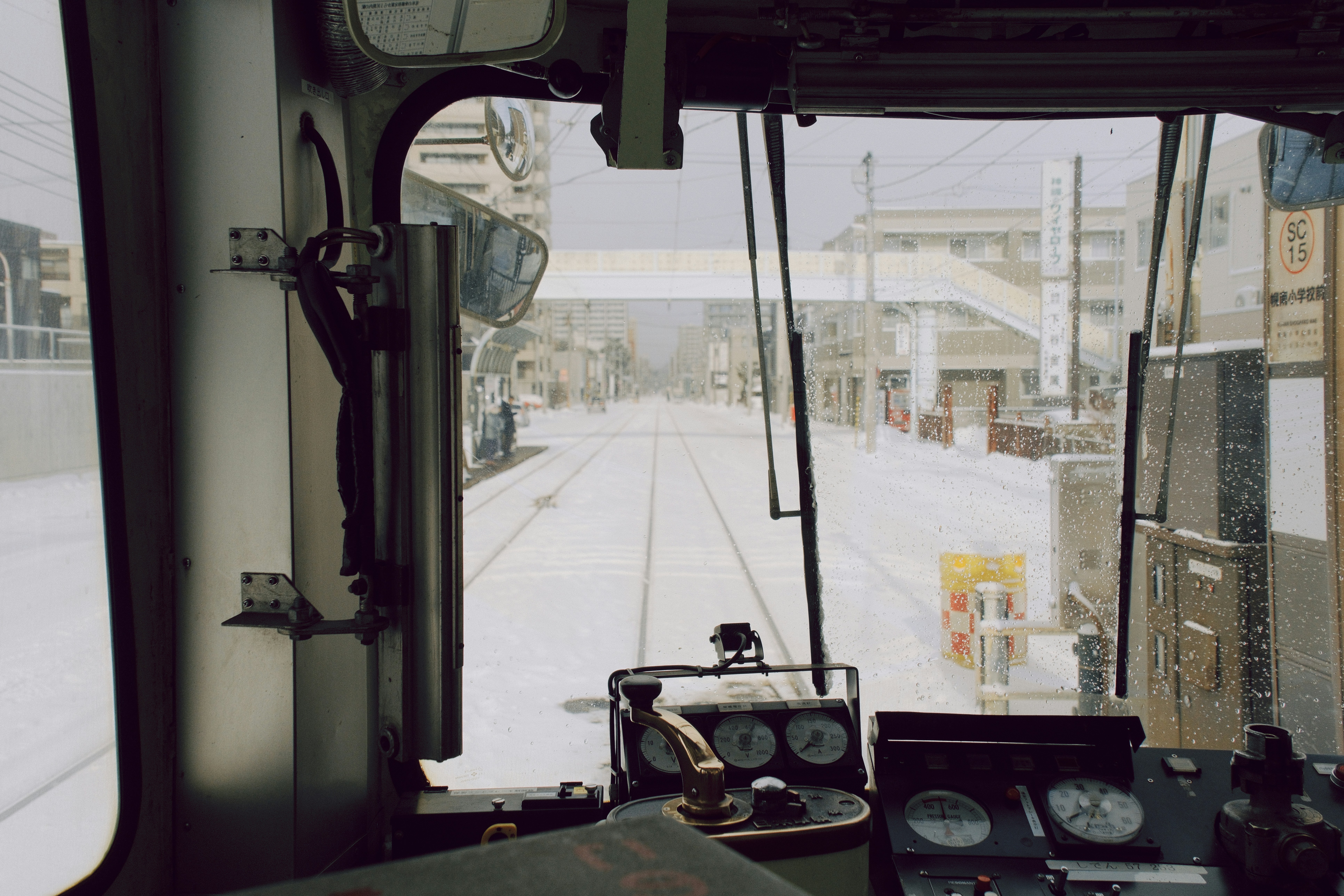View from train cabin during snowfall on tracks.