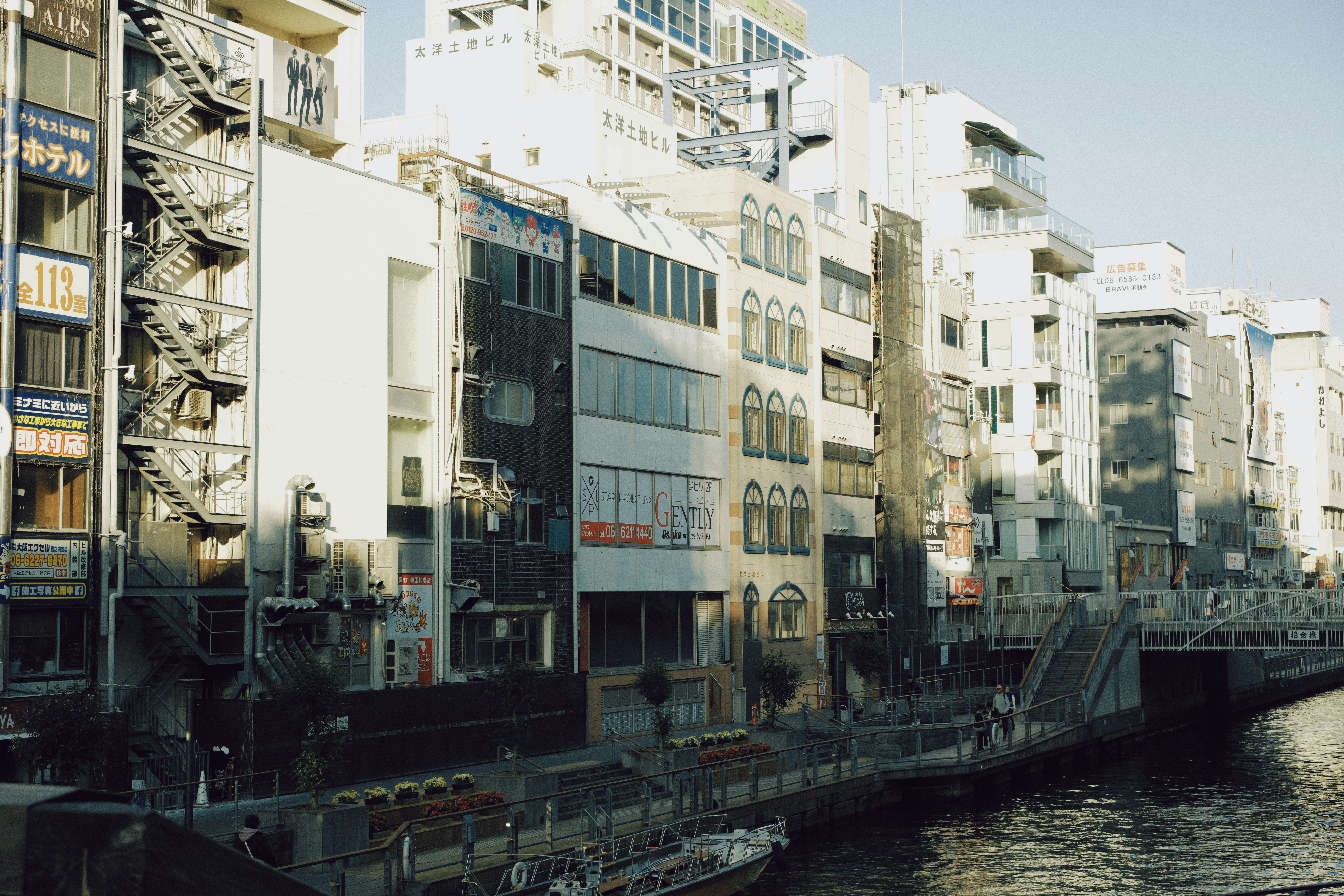 Buildings line a canal with a bridge in the distance.