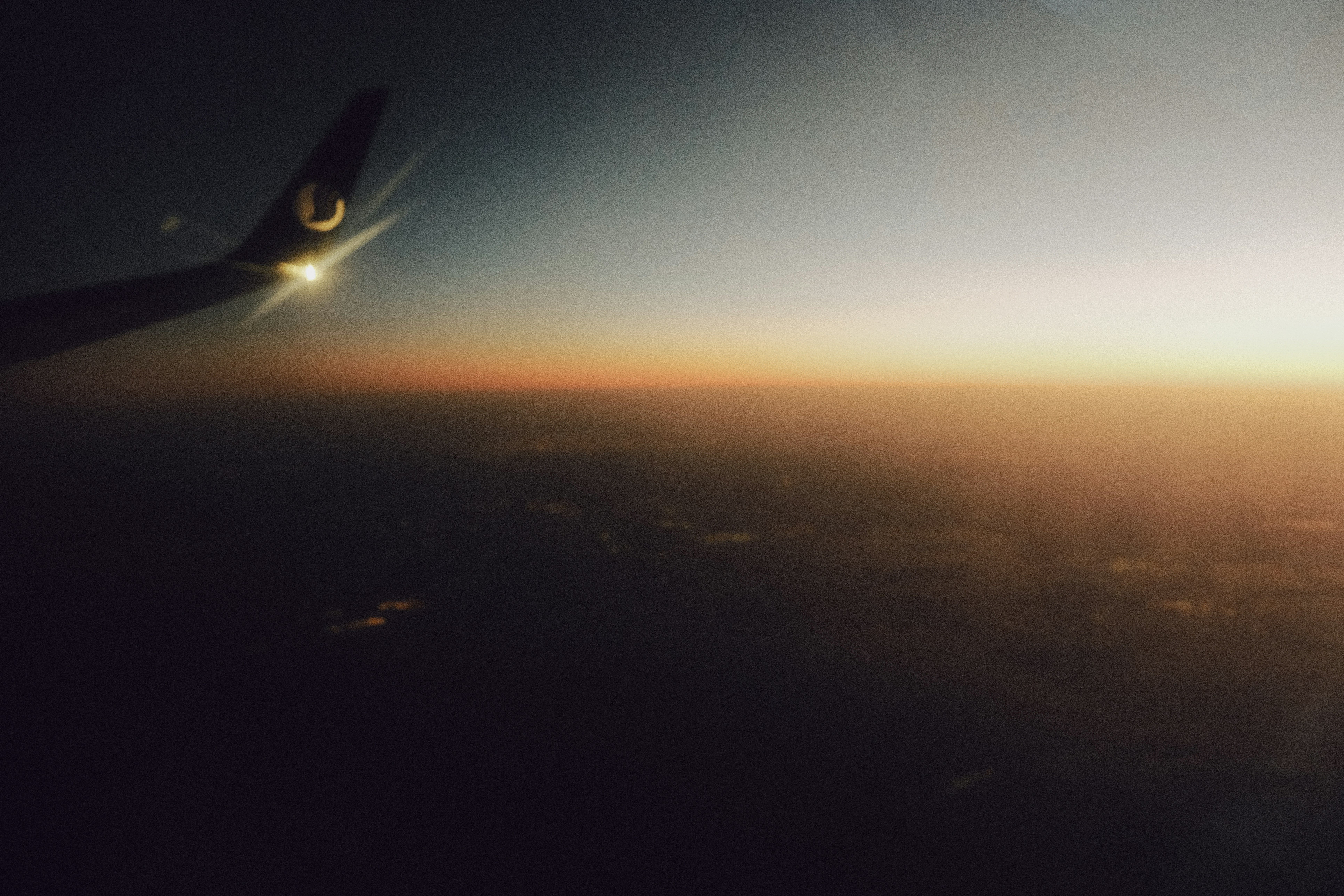 Airplane wing against a sunset sky over clouds.