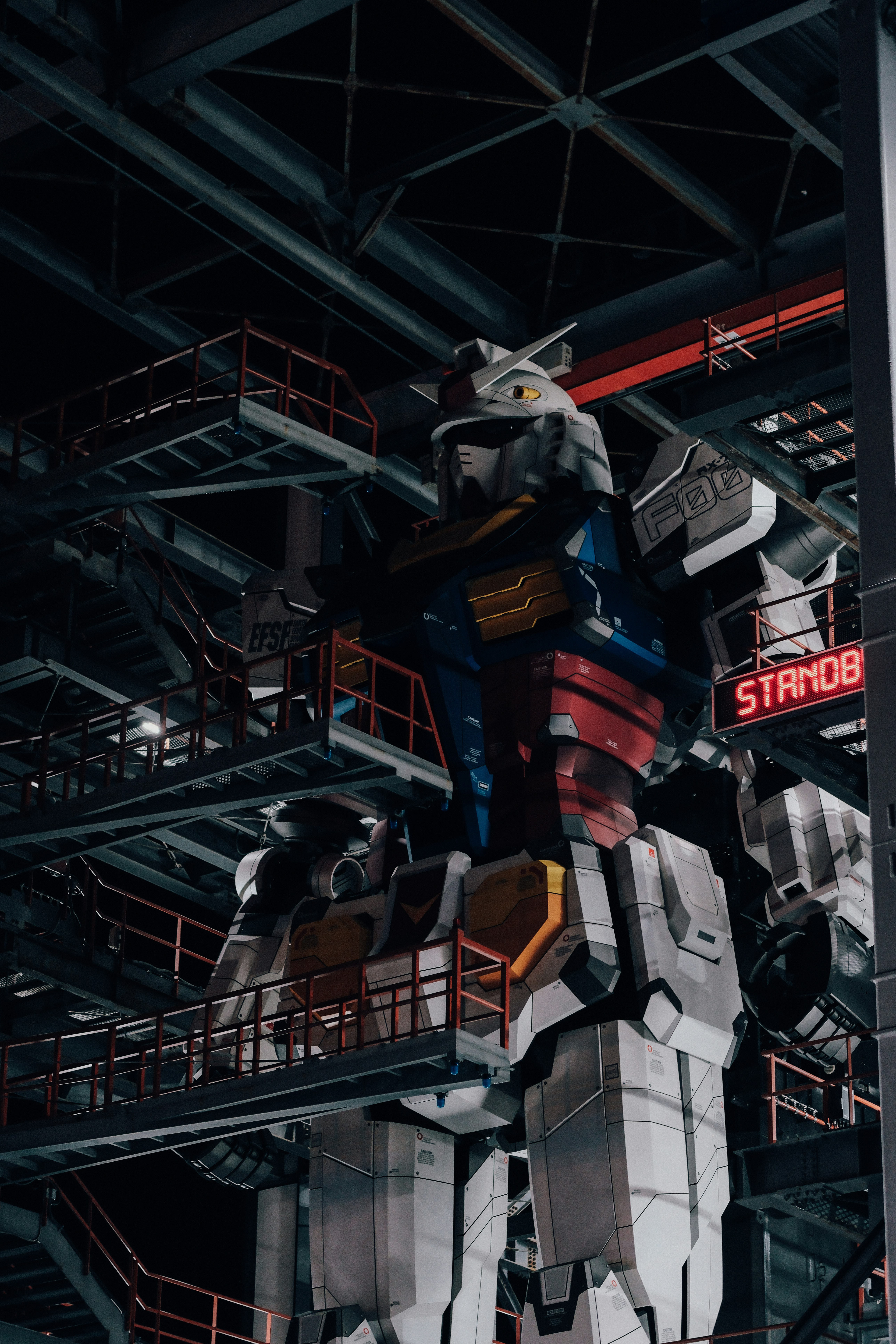 Giant gundam robot in a dark industrial setting