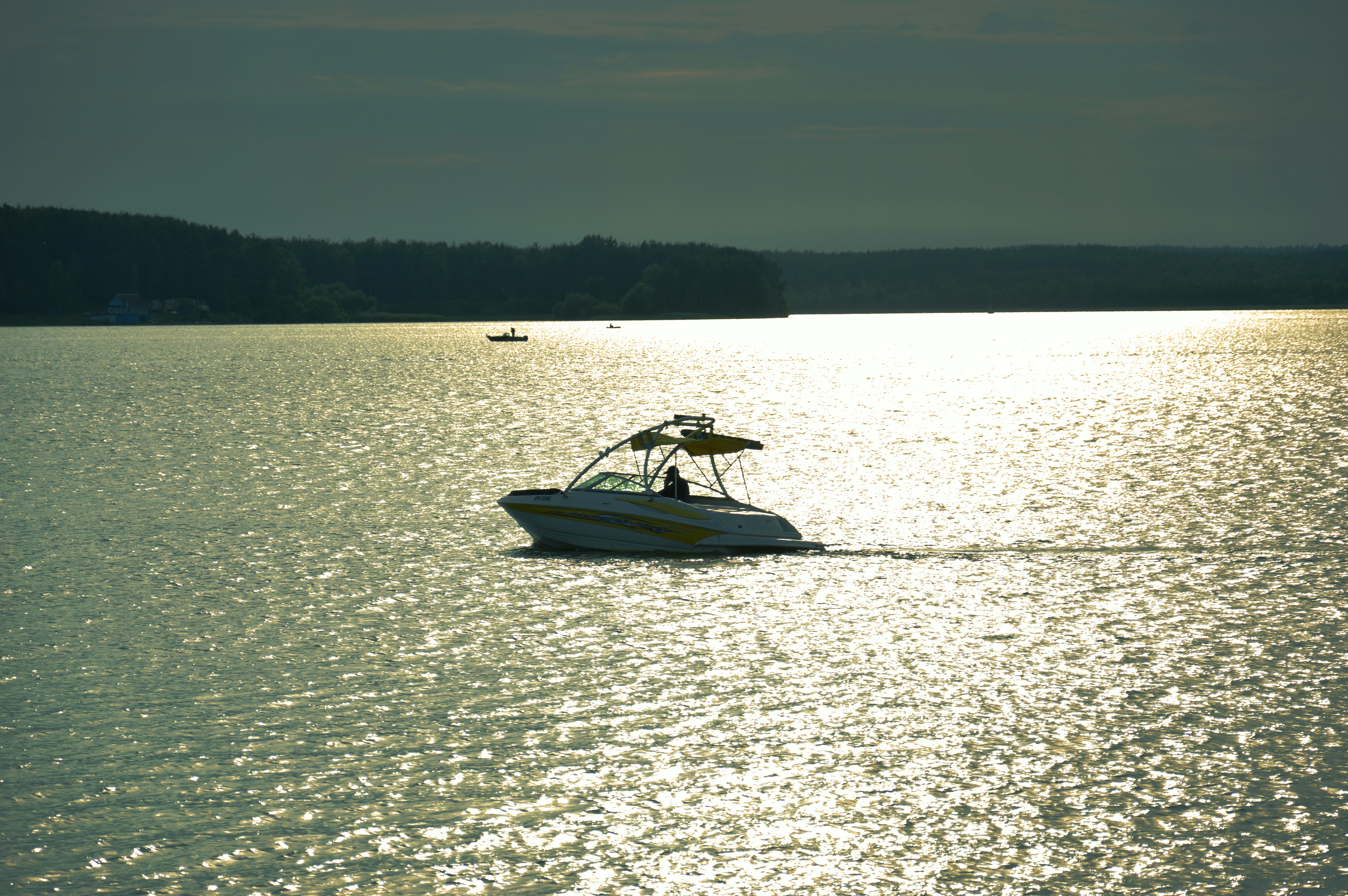 A motorboat navigates a shimmering lake at dusk, with soft reflections dancing on the water's surface.