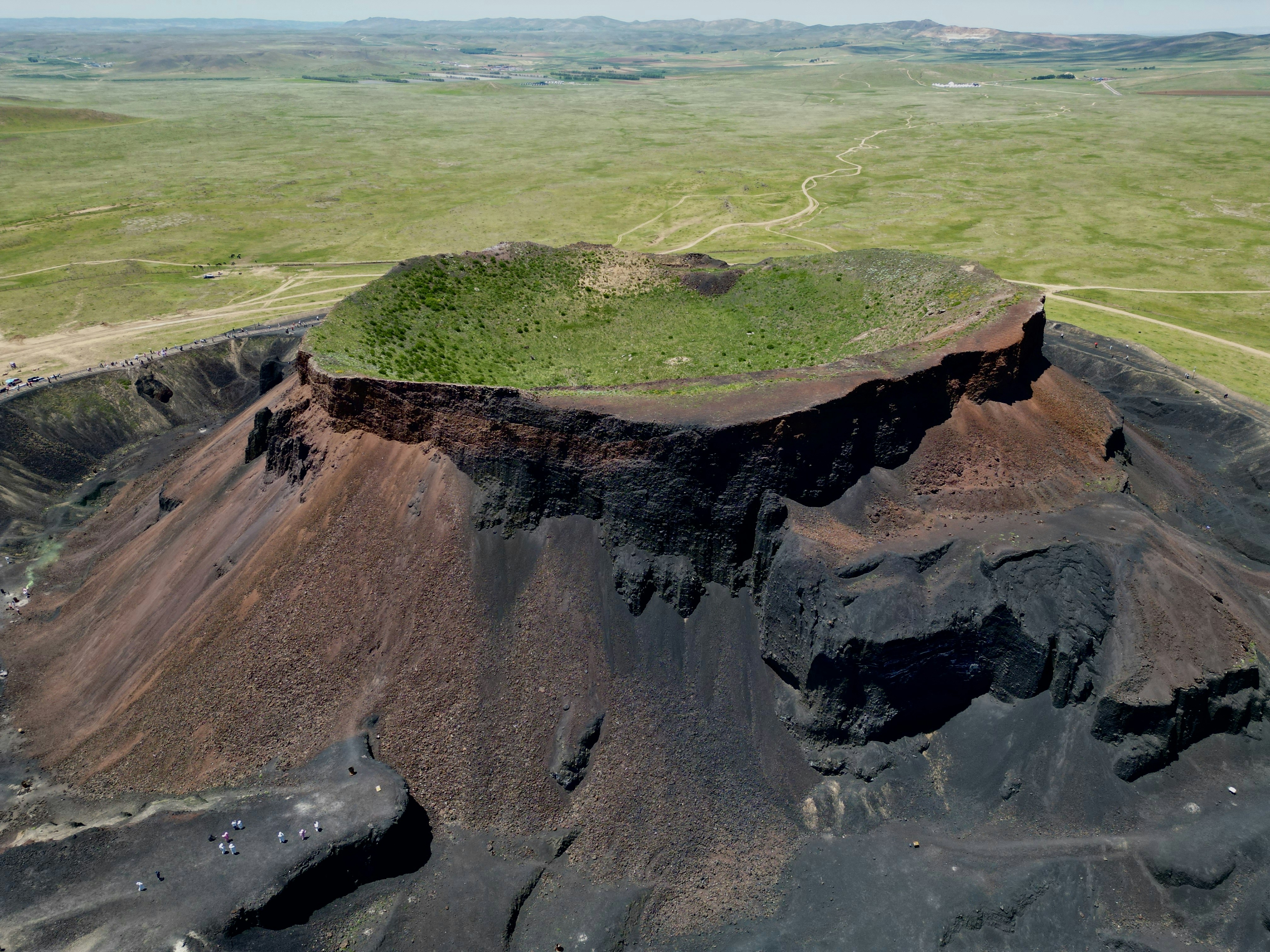 Crater of dormant volcano with green grass on rim