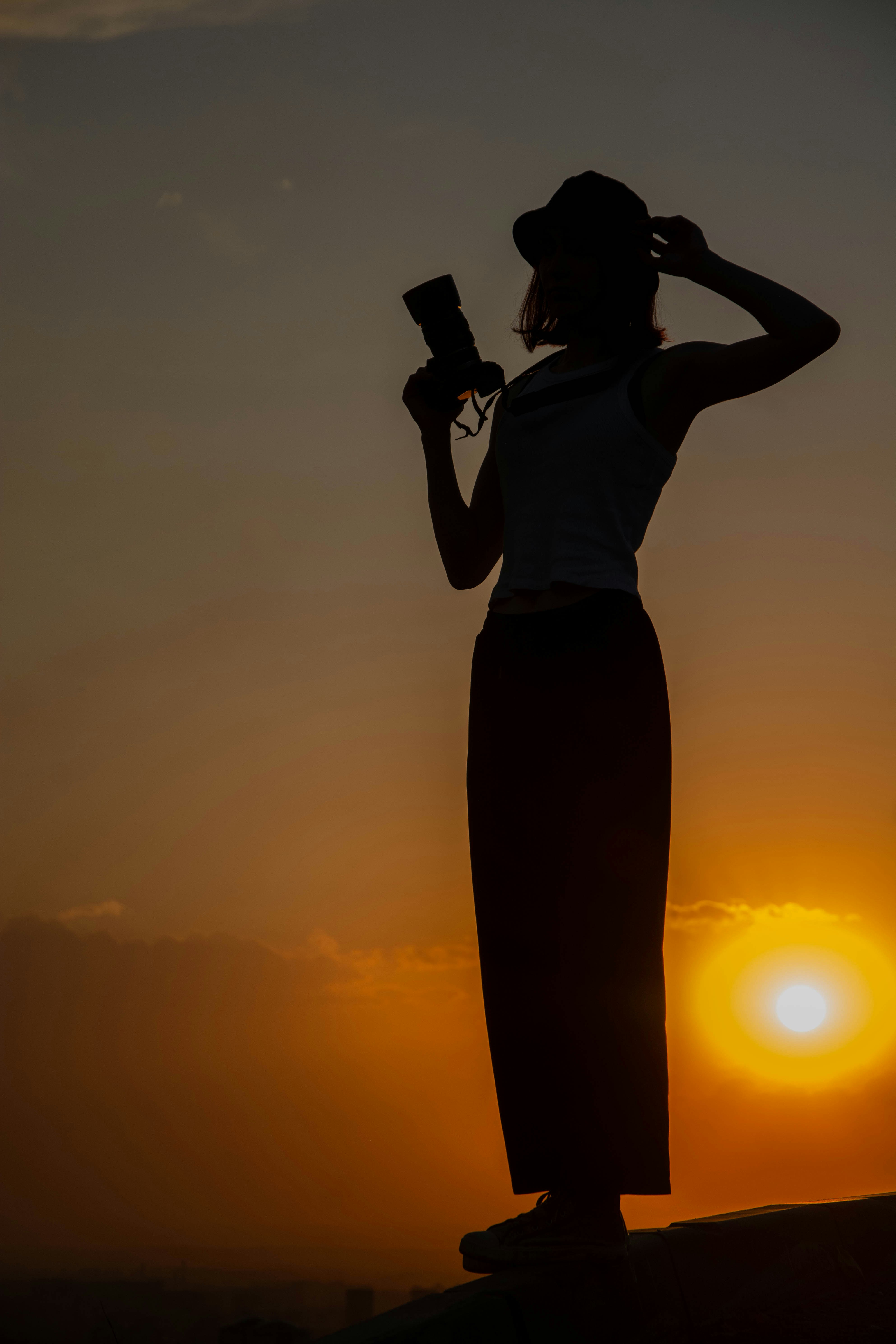 Silhouette of a photographer girl at sunset | Silhouette of a woman holding a camera at sunset