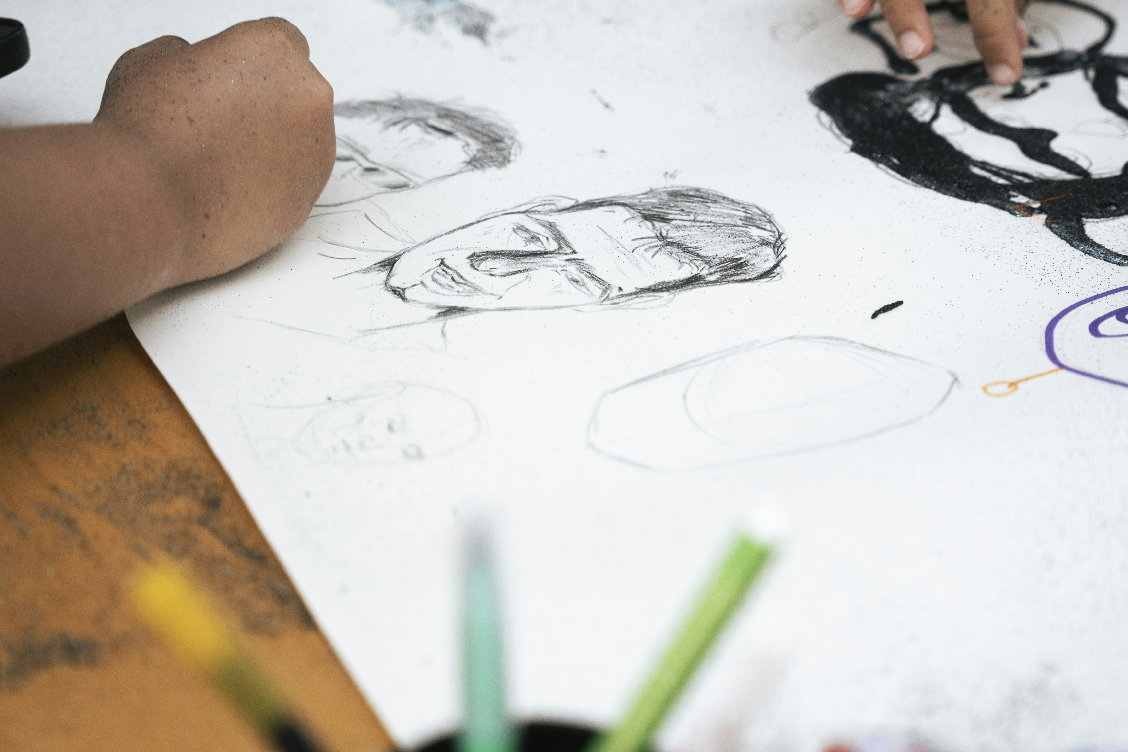 Children drawing faces on paper with pencils