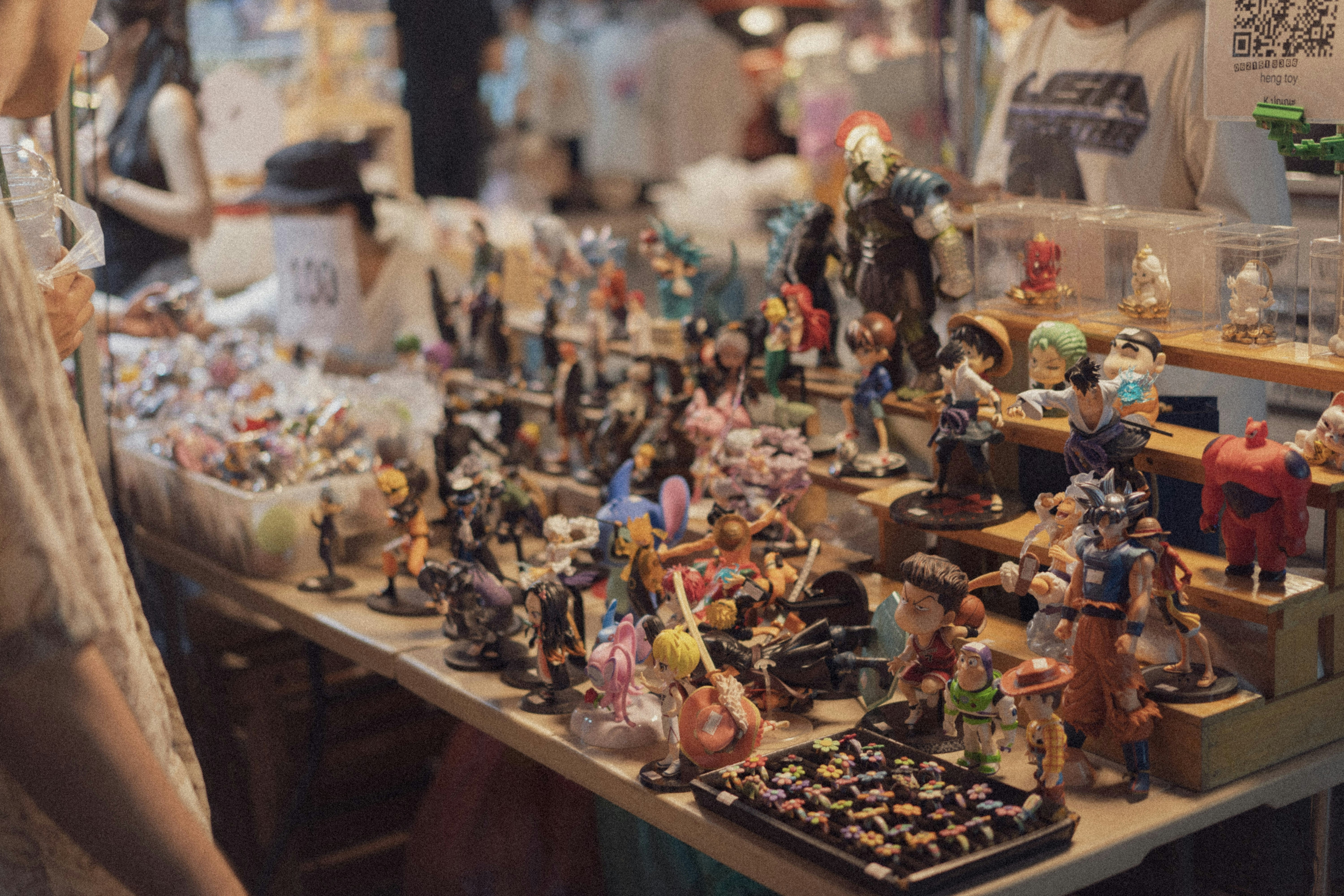A street market with cartoon character figurines. | Display table filled with assorted collectible figurines.