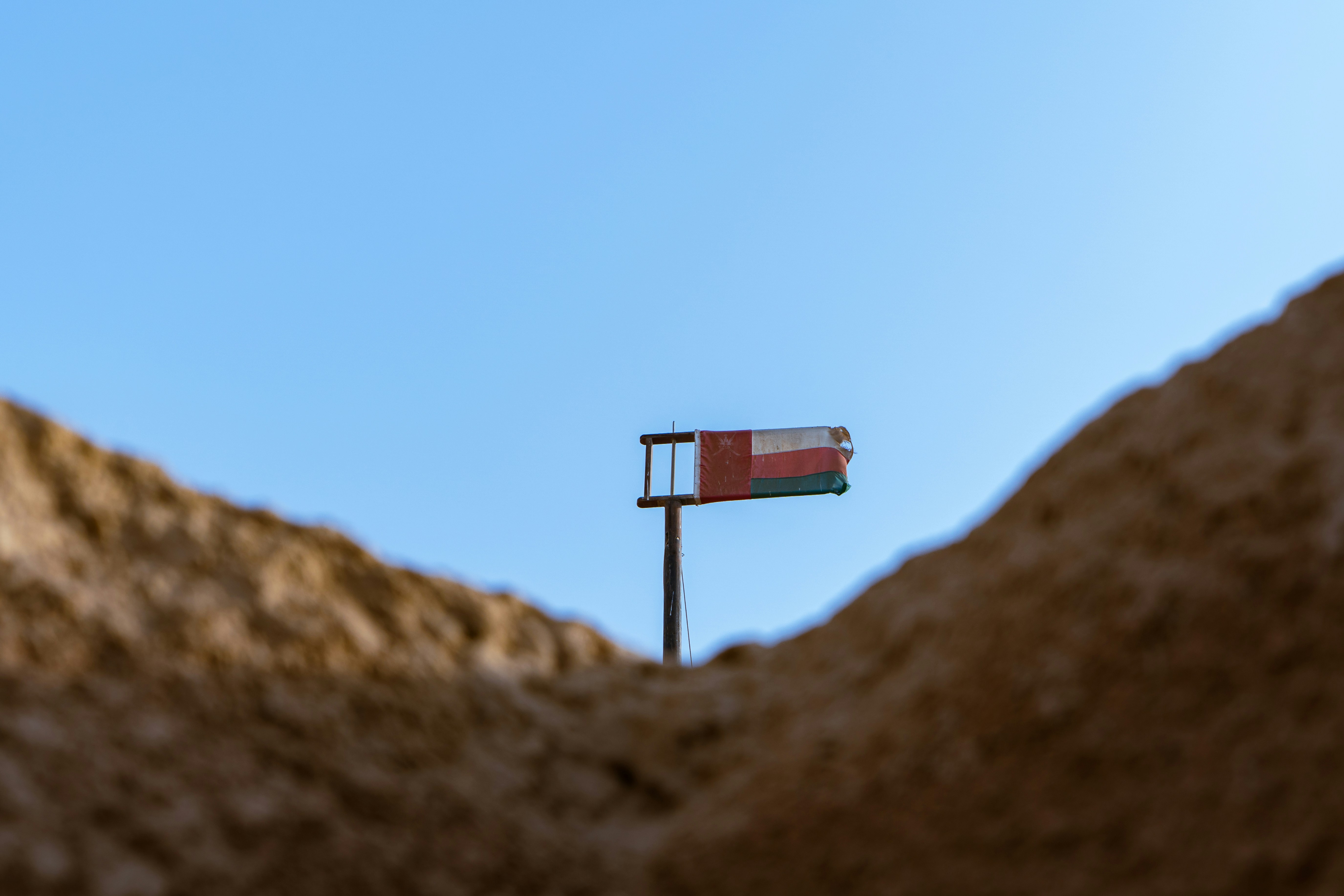 Lone flag on a dirt ridge under a crisp blue sky