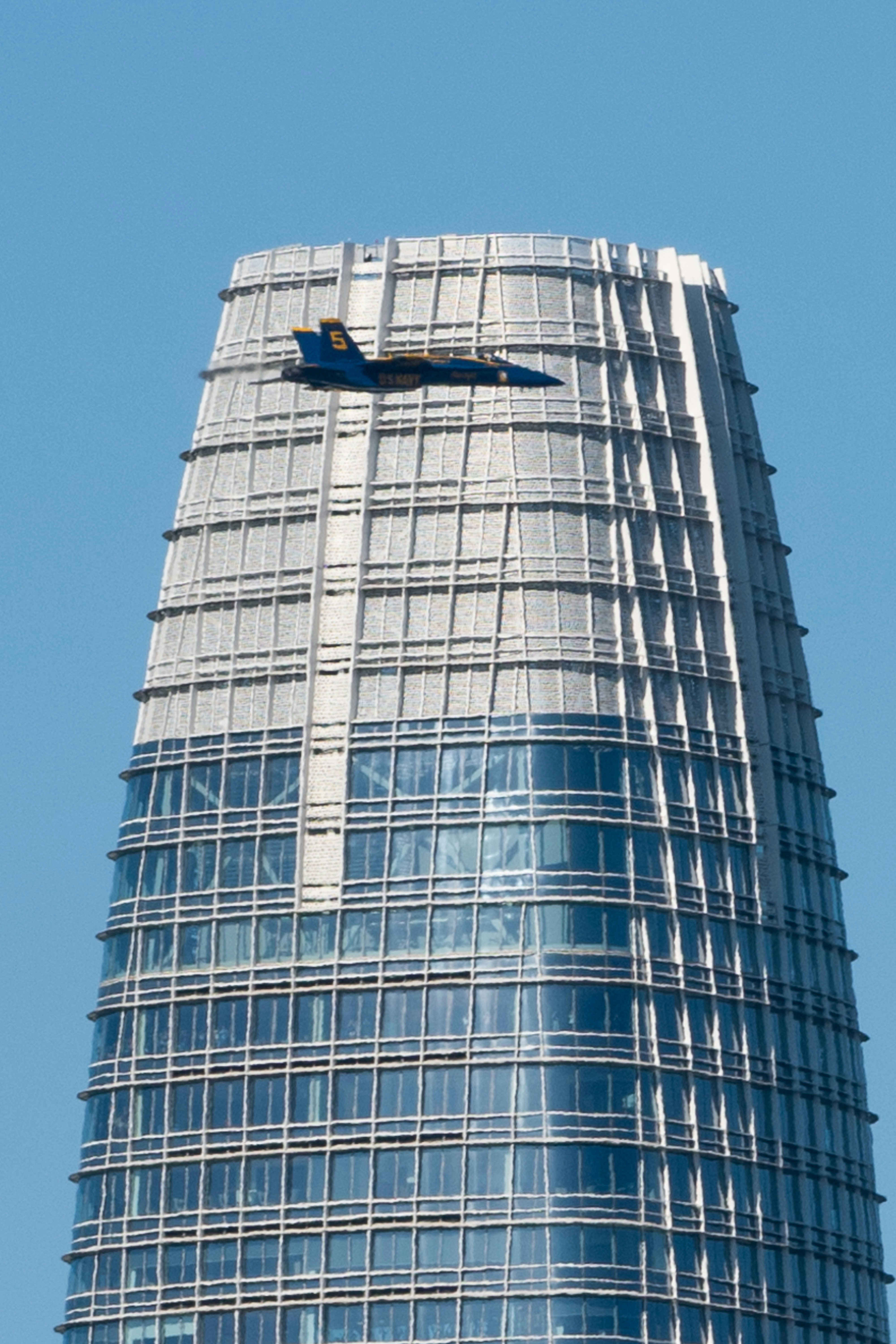 Fighter jet soaring past a modern skyscraper, showcasing the intersection of technology and architecture.