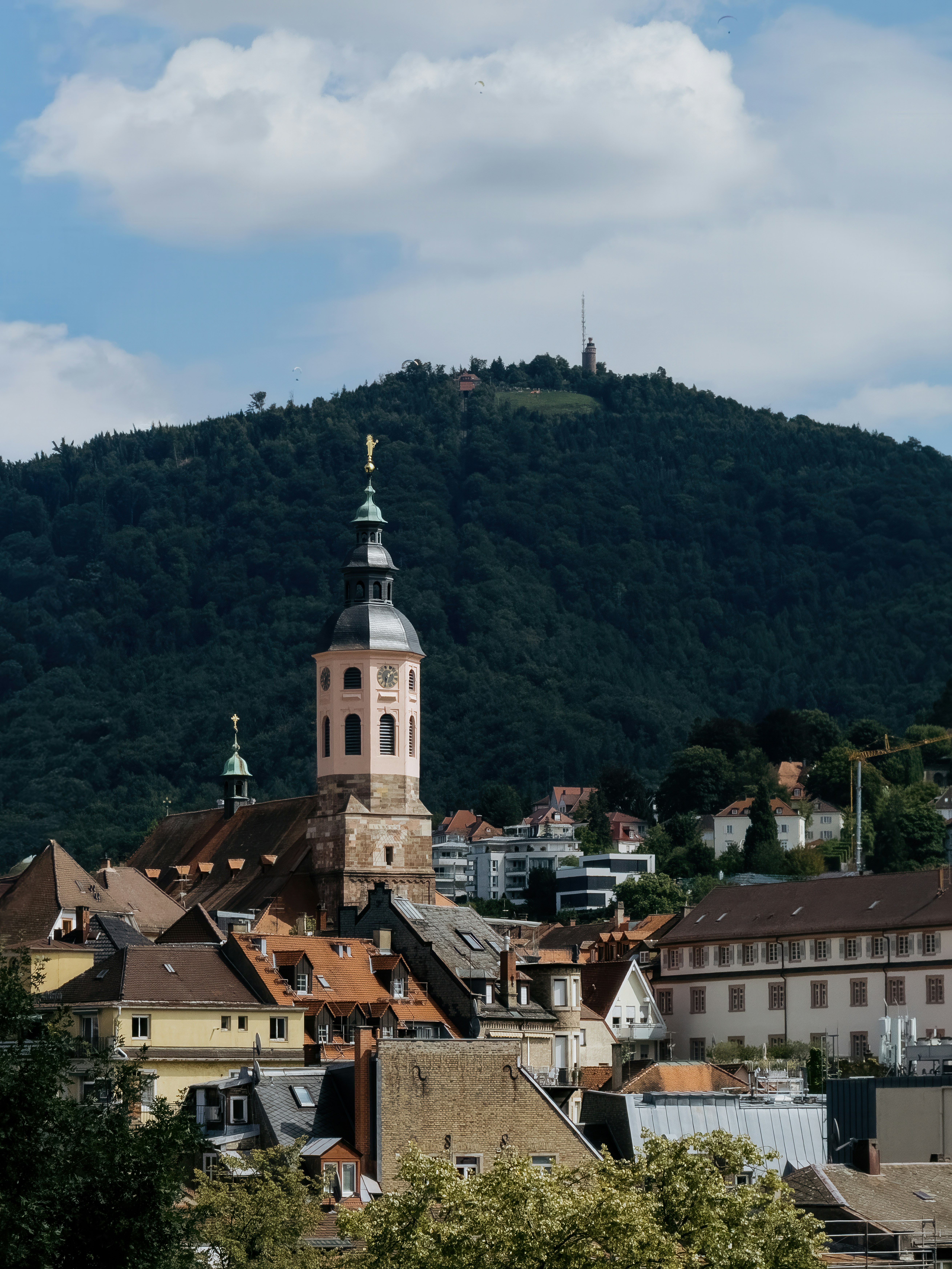 Town with church steeple below forested hill