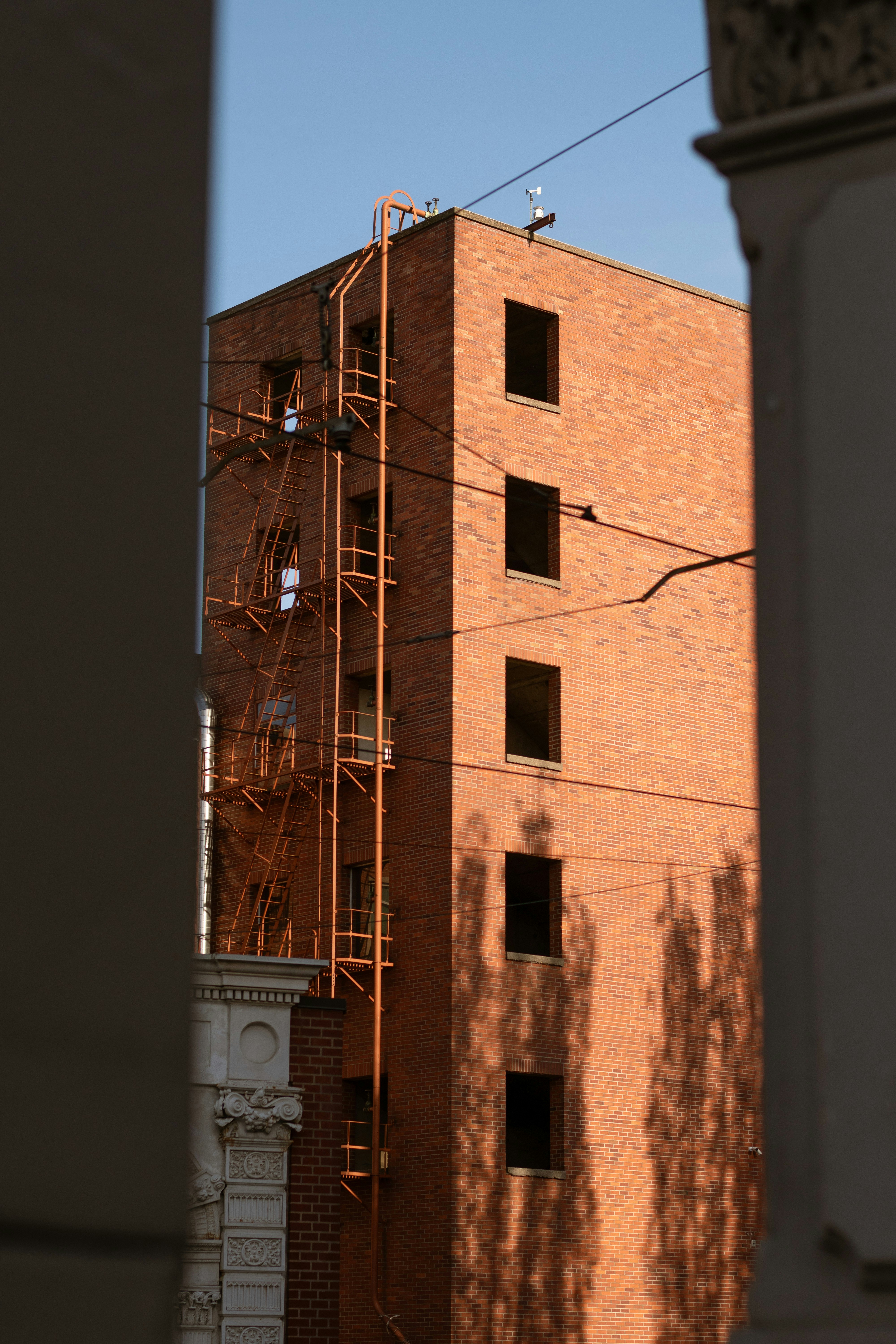Red building in Portland | Brick building with fire escape and shadows.