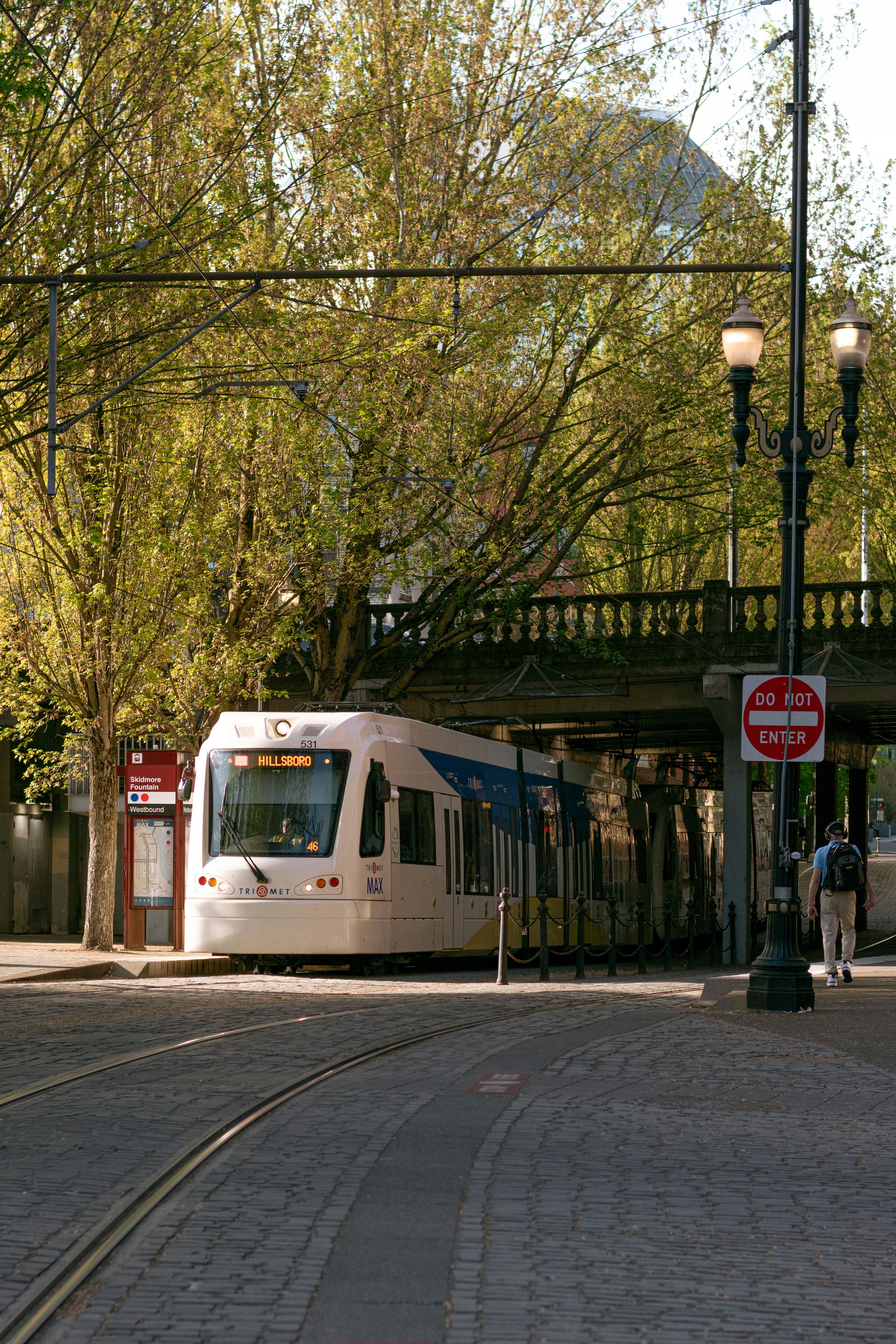 MAX metro rail car in downtown Portland | A modern tram stops at a station under an overpass.