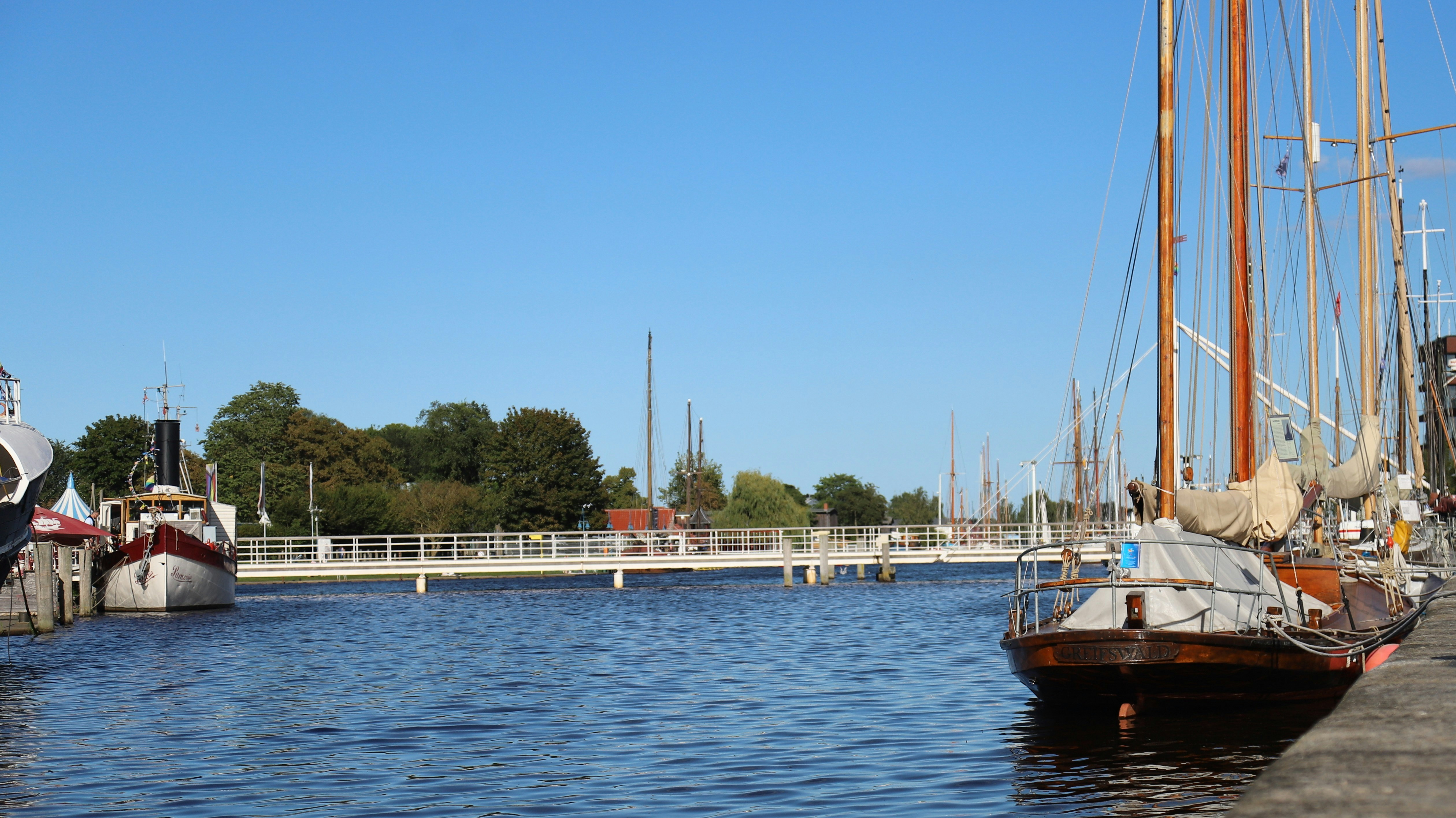 Sailboats moored peacefully in a calm harbor under a clear blue sky, showcasing the tranquility of maritime life.