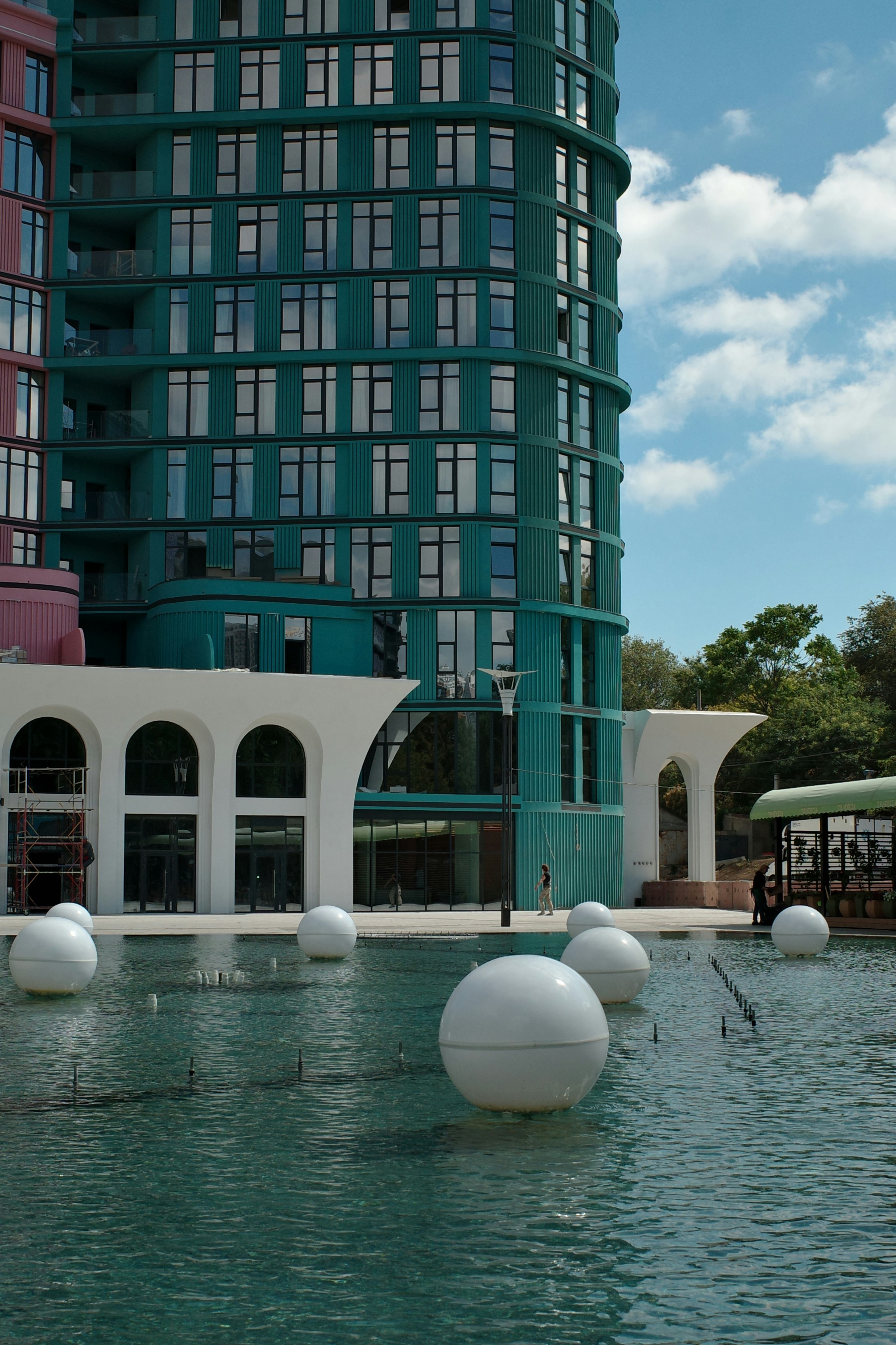 Modern teal building with arched entrance and floating spheres. photo ...