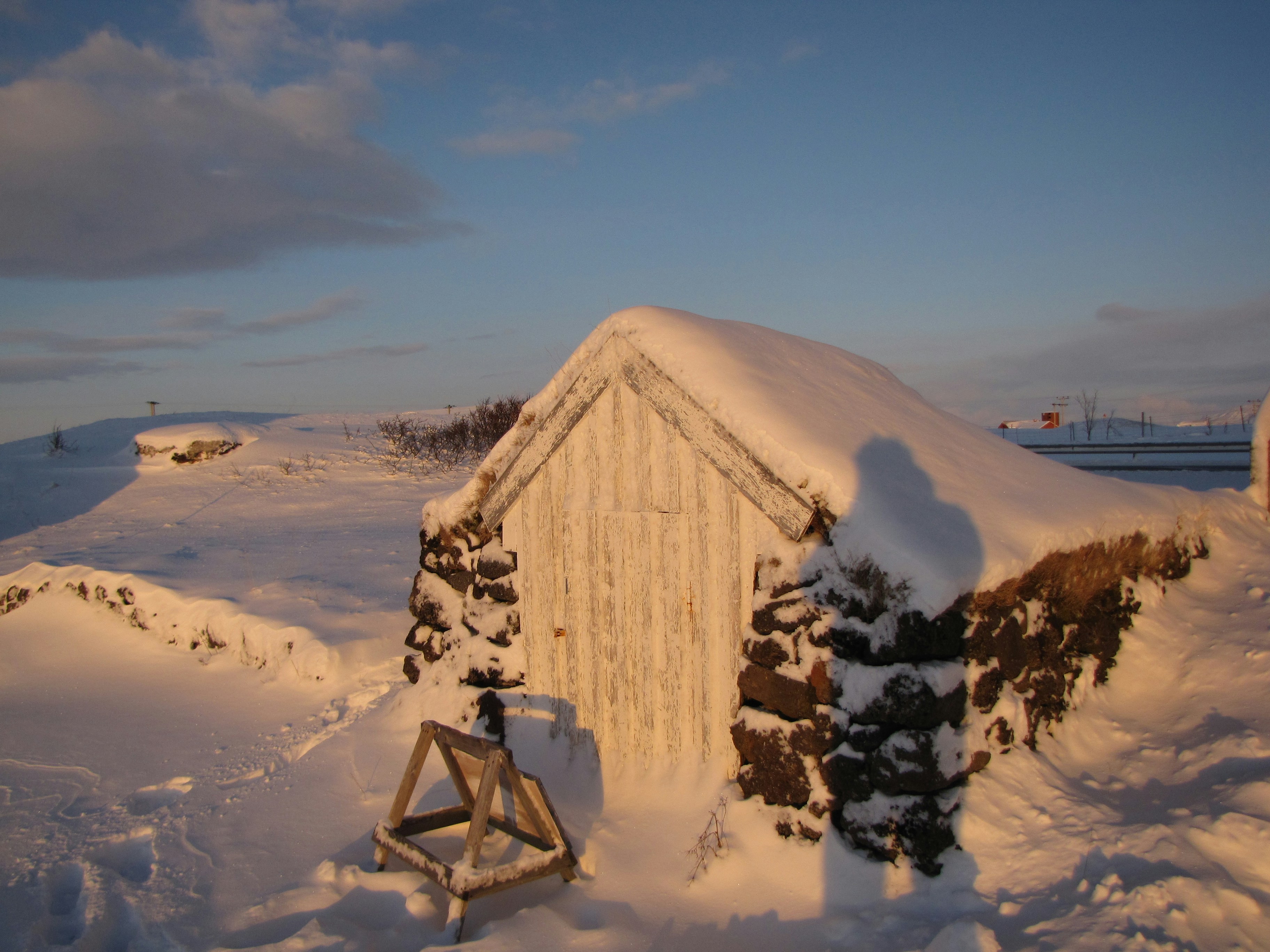 Snow covered building with stone foundation at sunset