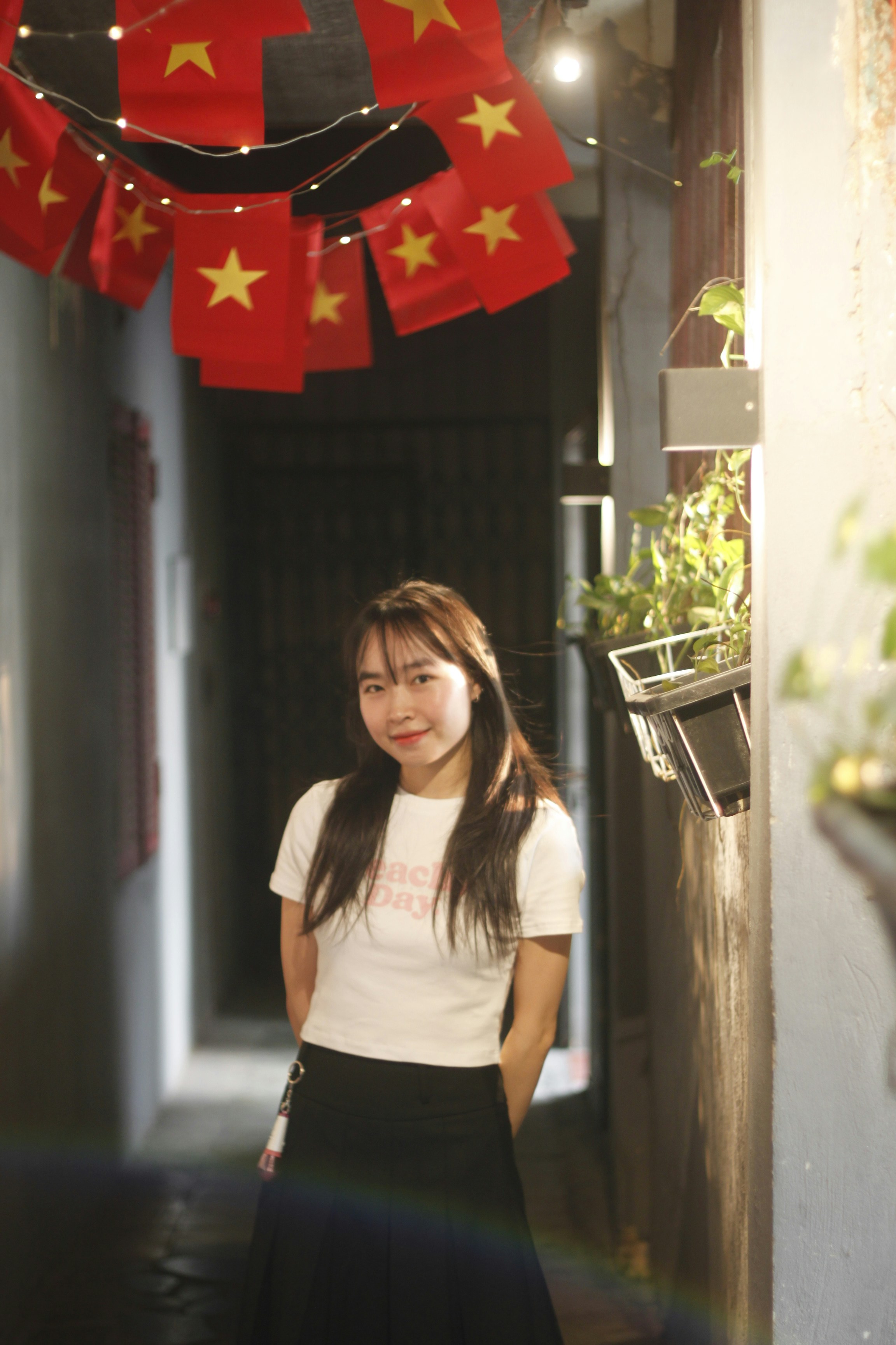 Young woman standing in a narrow alleyway with flags.