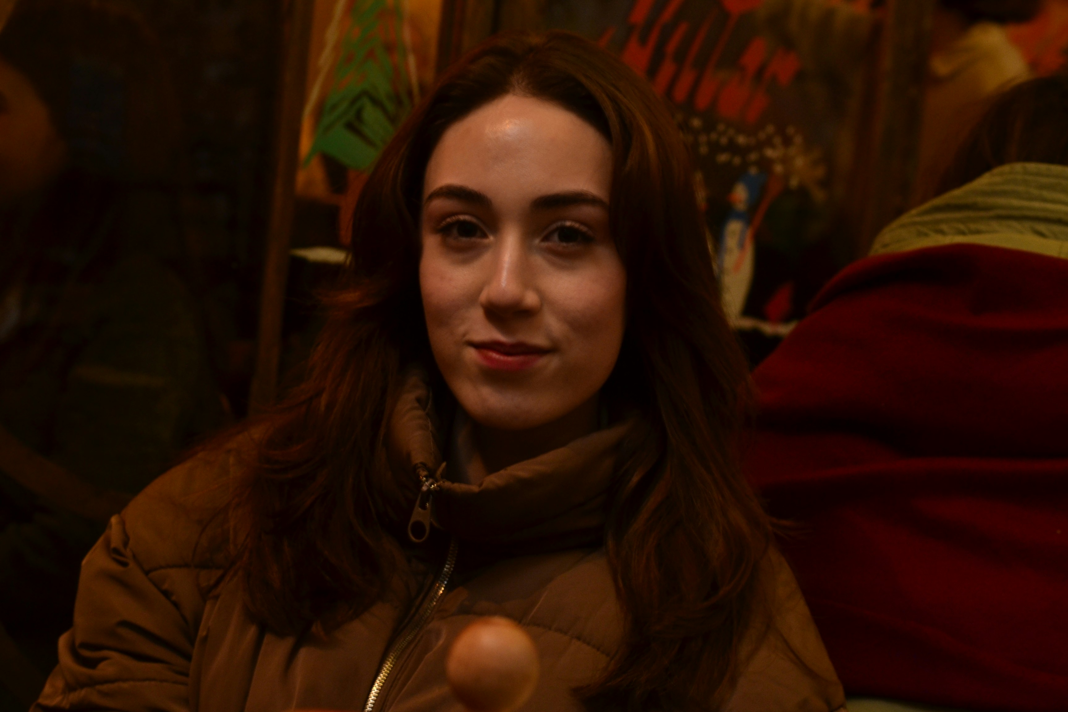 Young woman with long brown hair wearing a brown jacket