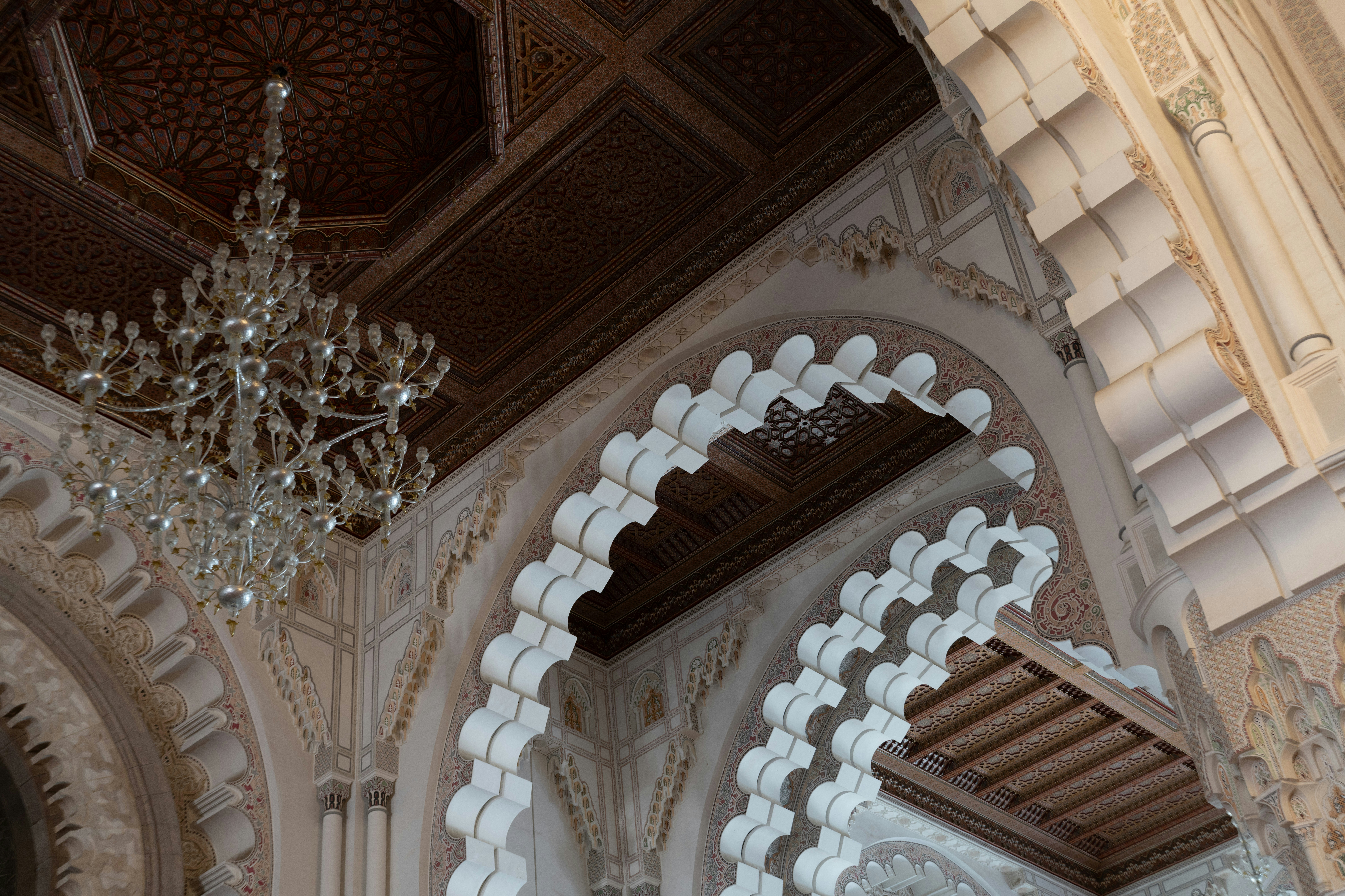 Ornate chandelier hangs in a room with arched doorways.