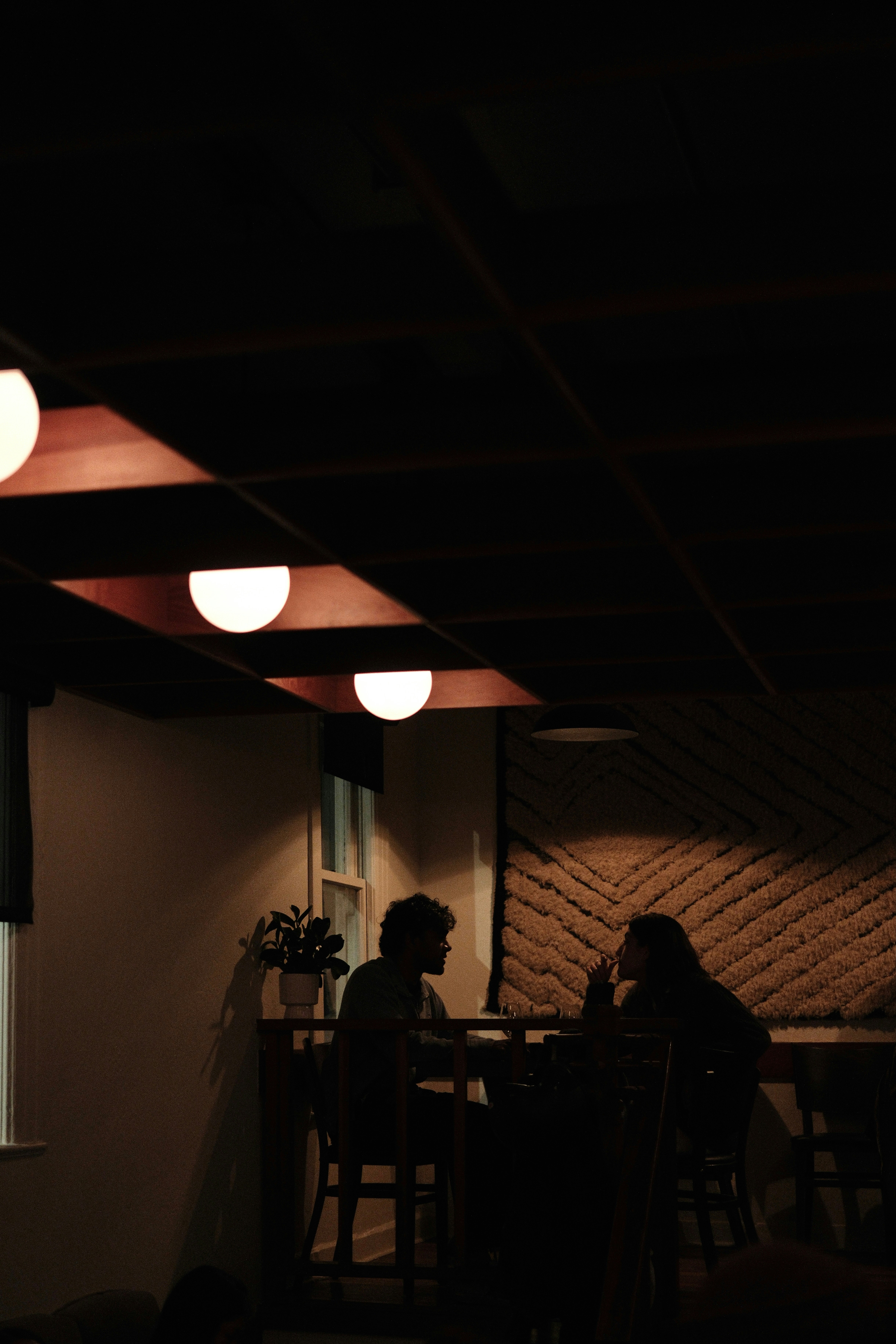 Two people silhouetted at a table in a dimly lit room.