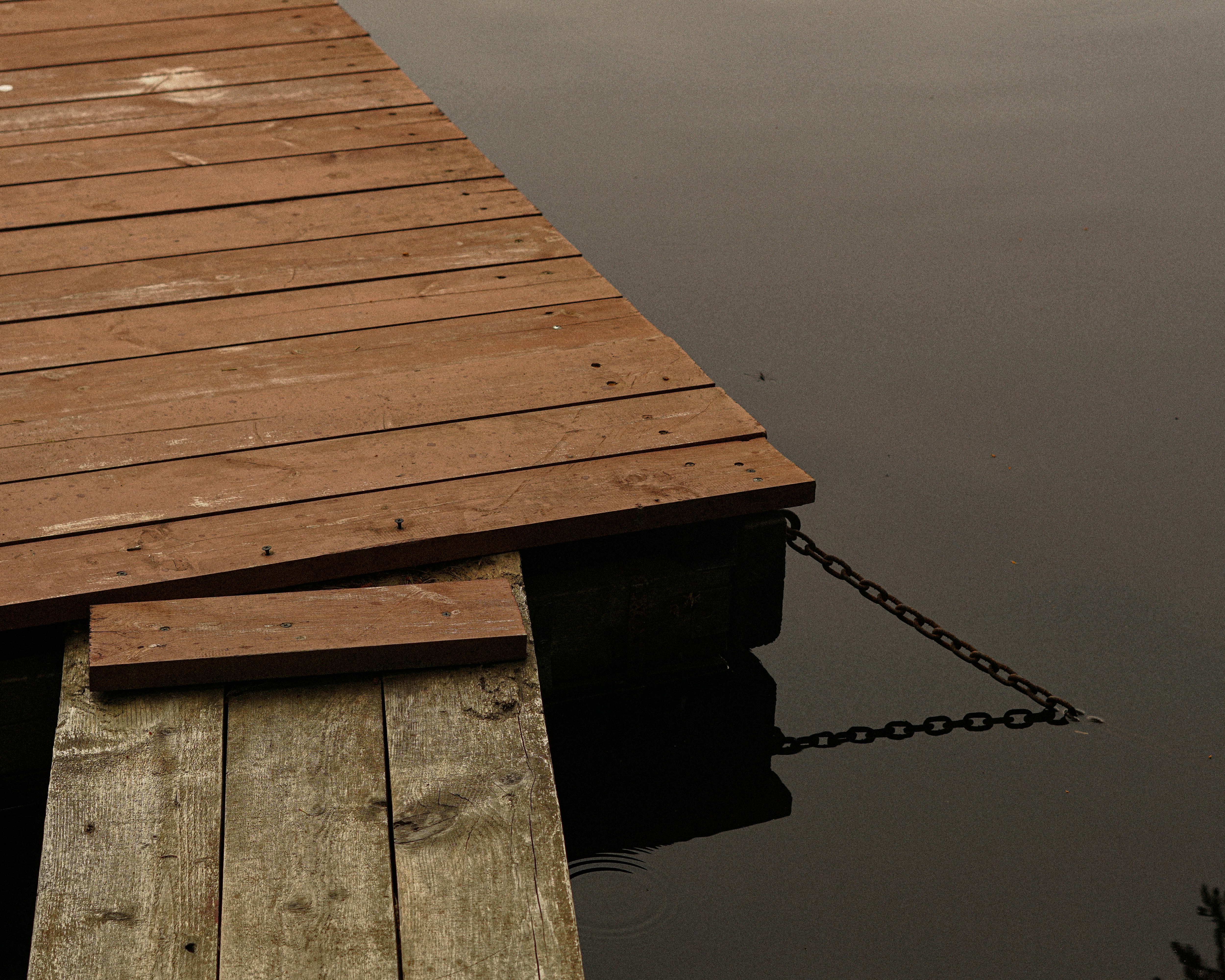 Wooden dock extending over dark, still water