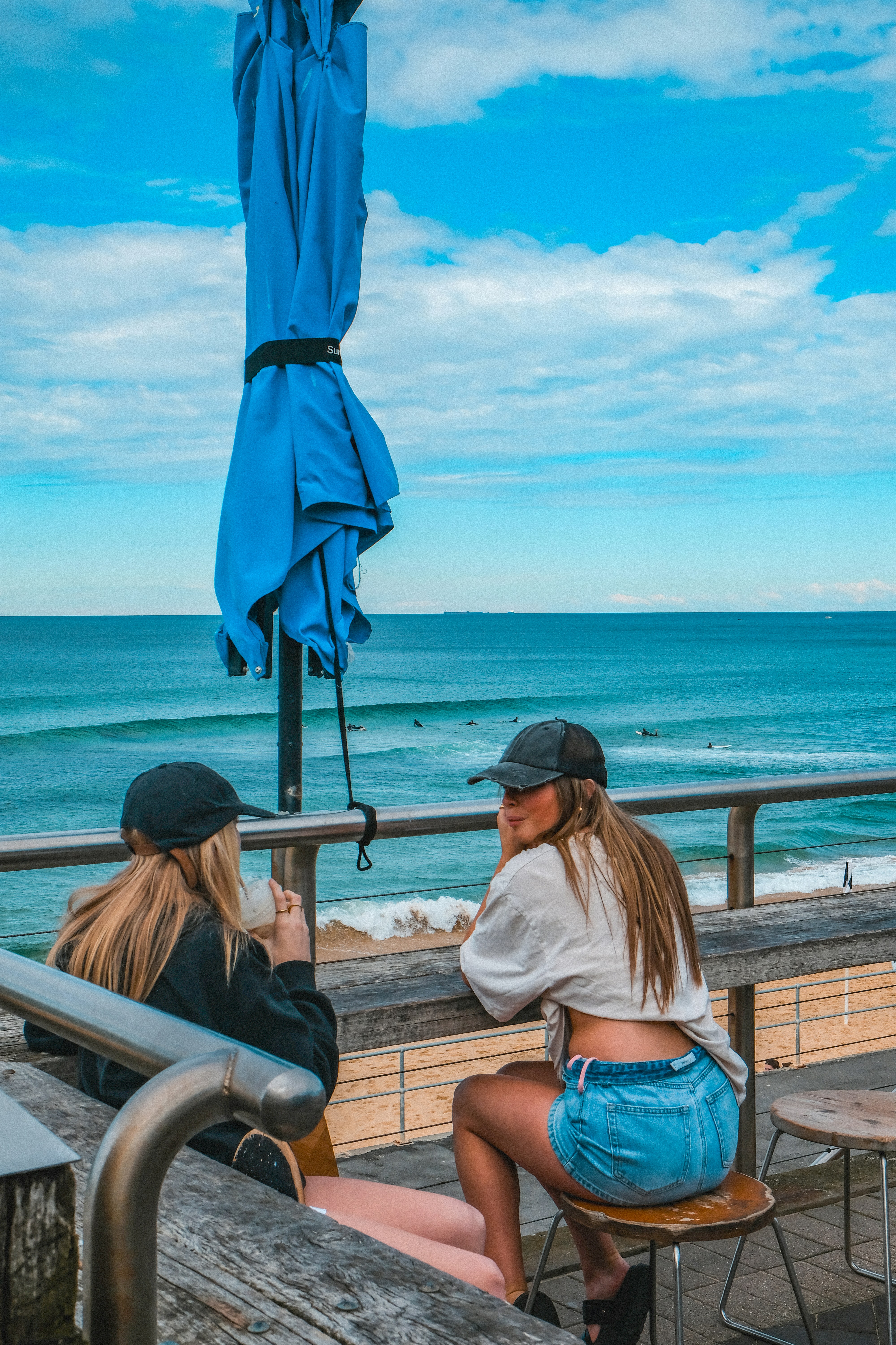 girls hanging out in summer | Two women facing the ocean on a sunny day.