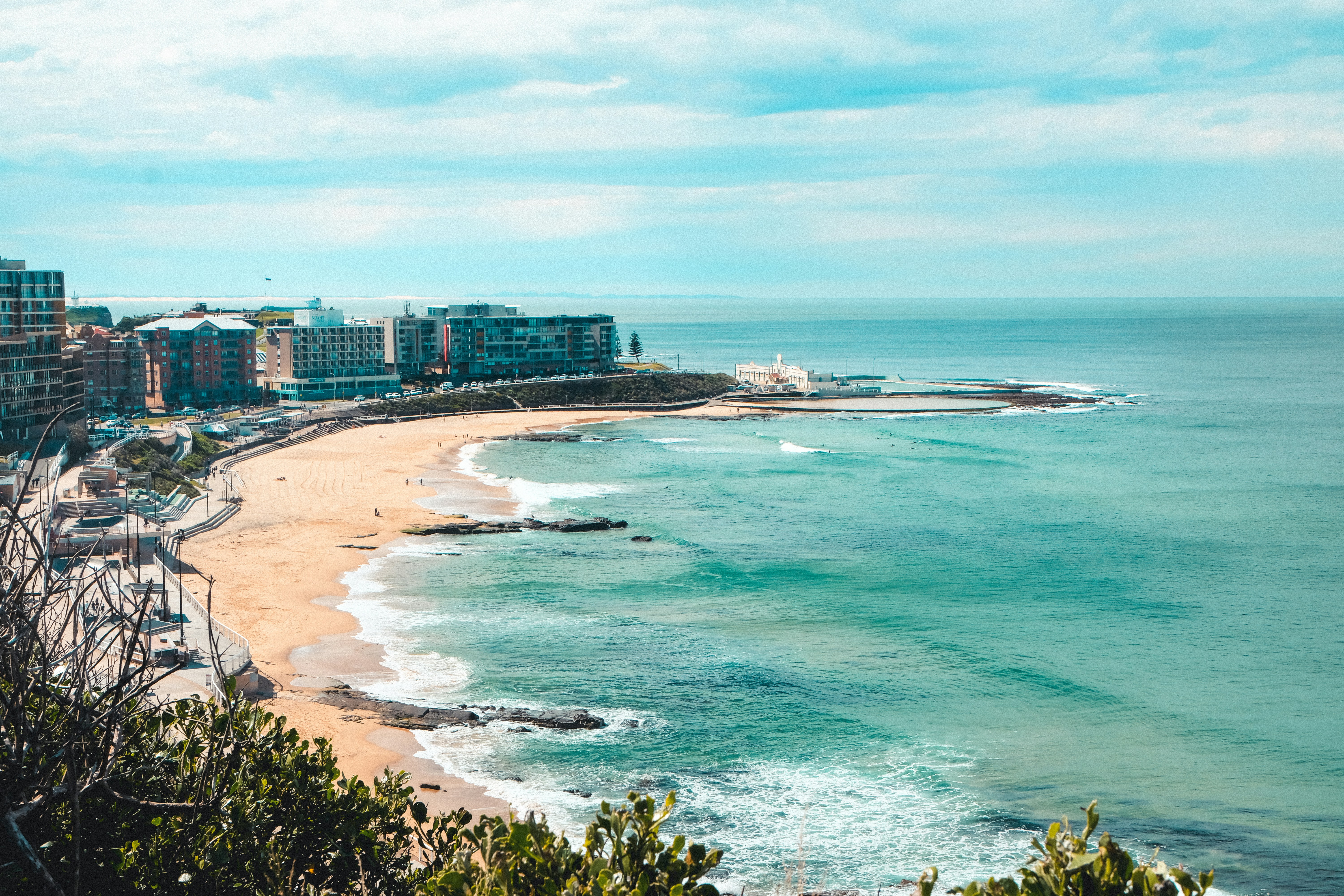 Coastal city skyline along a sandy beach and ocean.