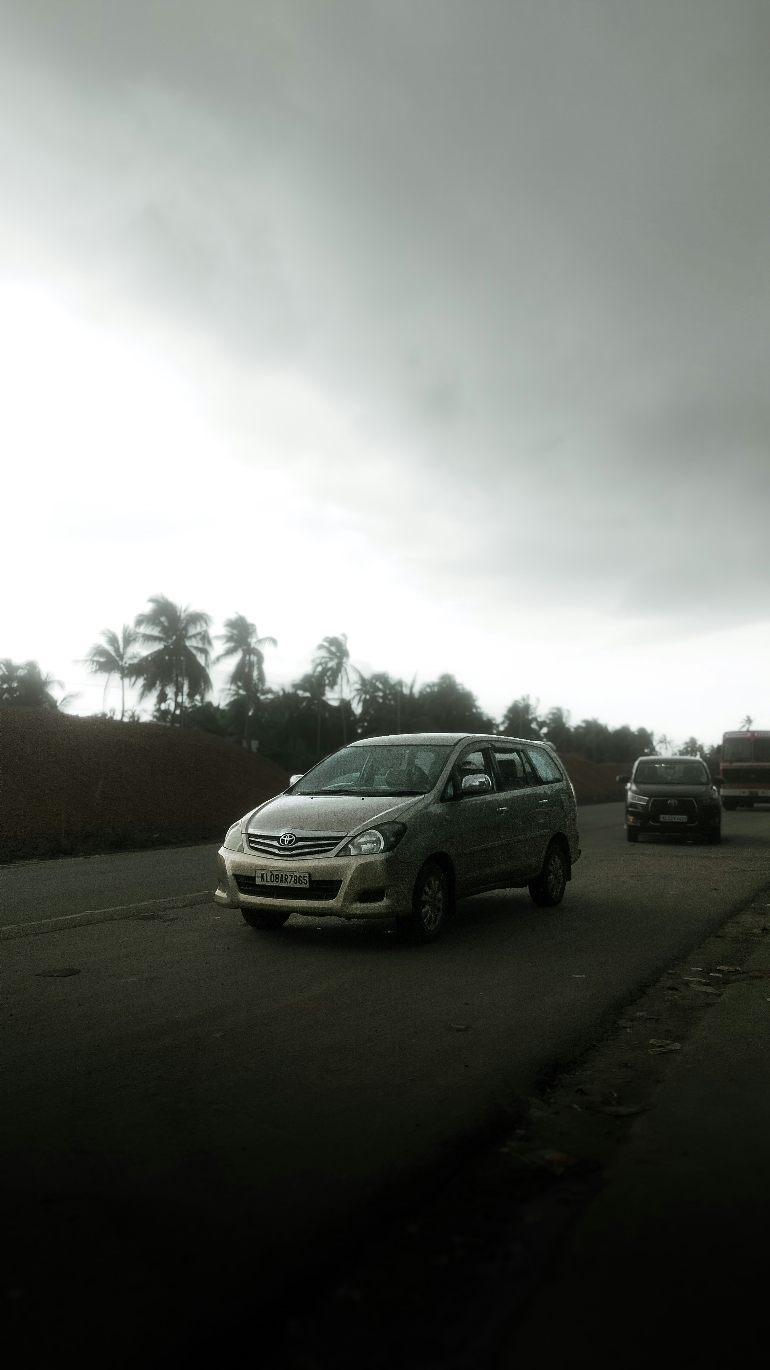 Cars driving on a road under a cloudy sky.