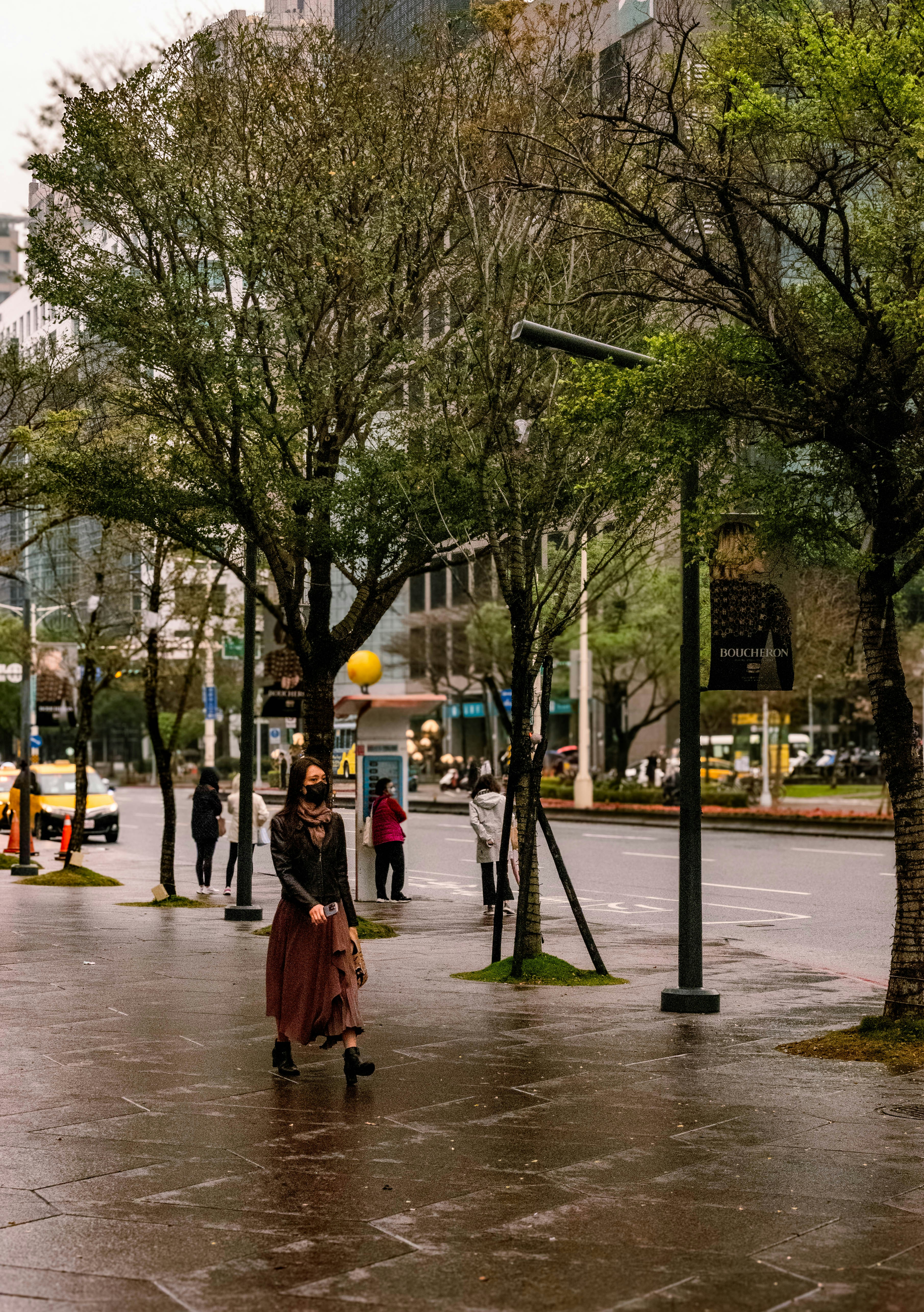 Woman walking on wet sidewalk in city street