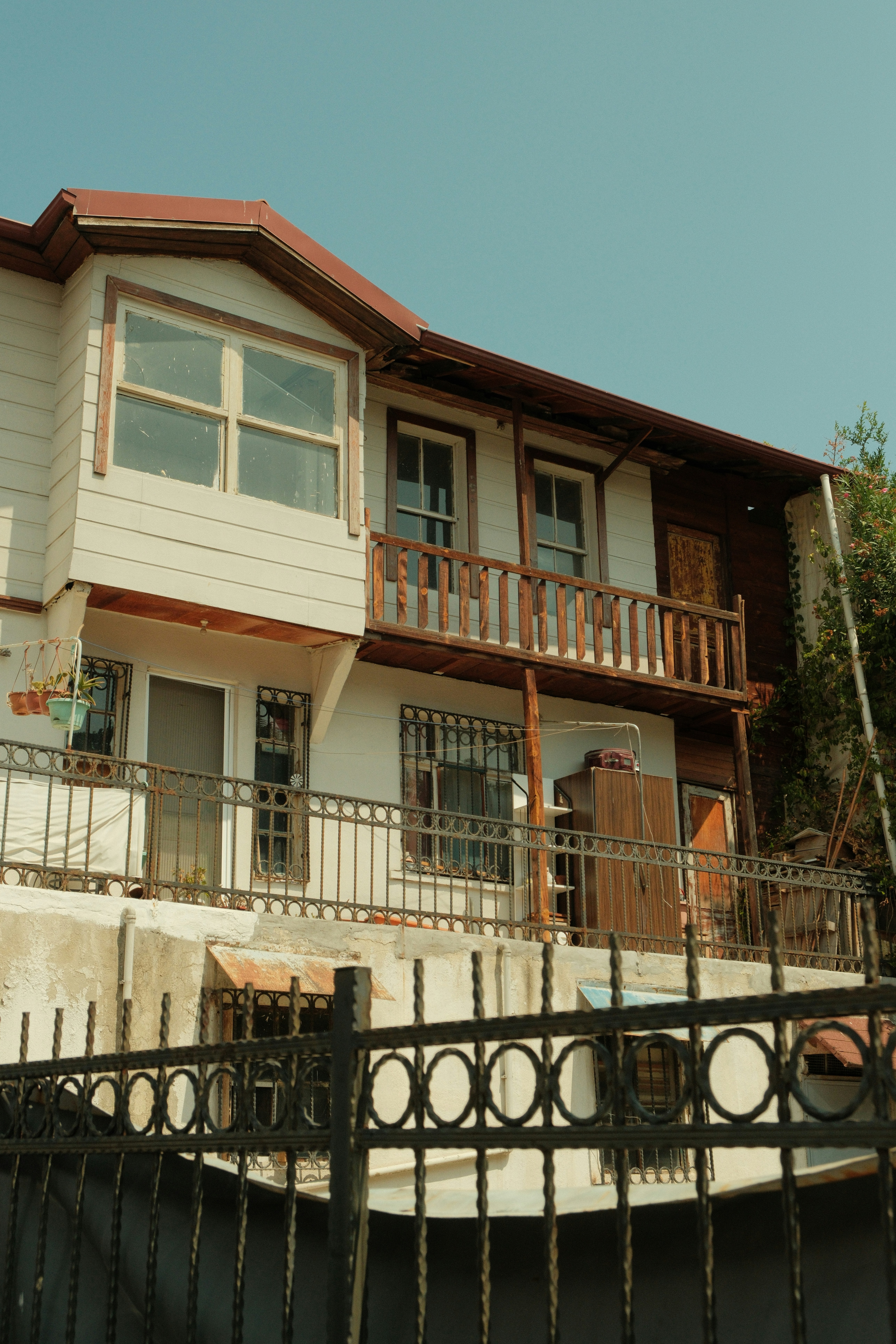 A weathered wooden house with a balcony and fence.