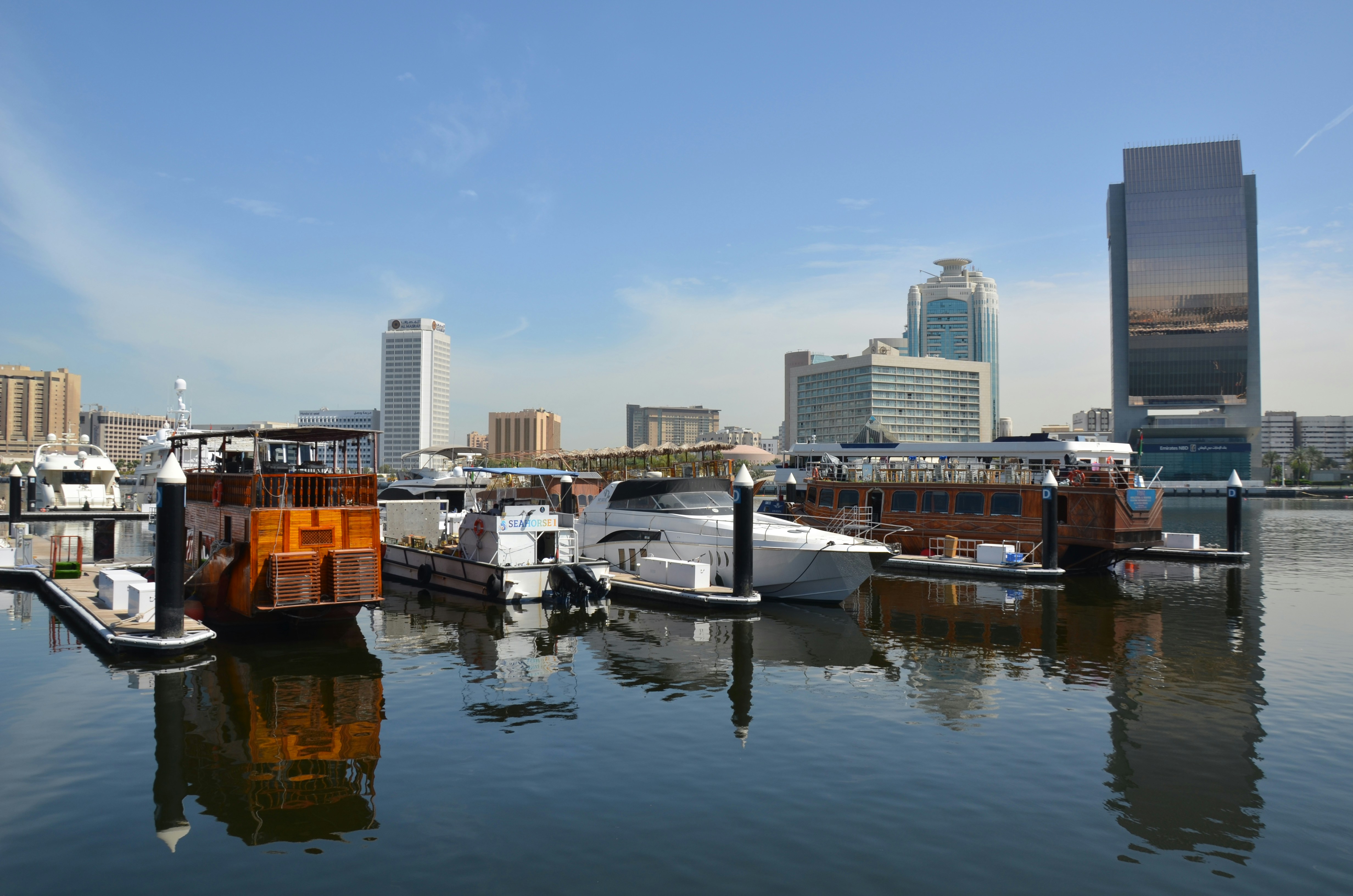 Boats docked in a harbor with city skyline.