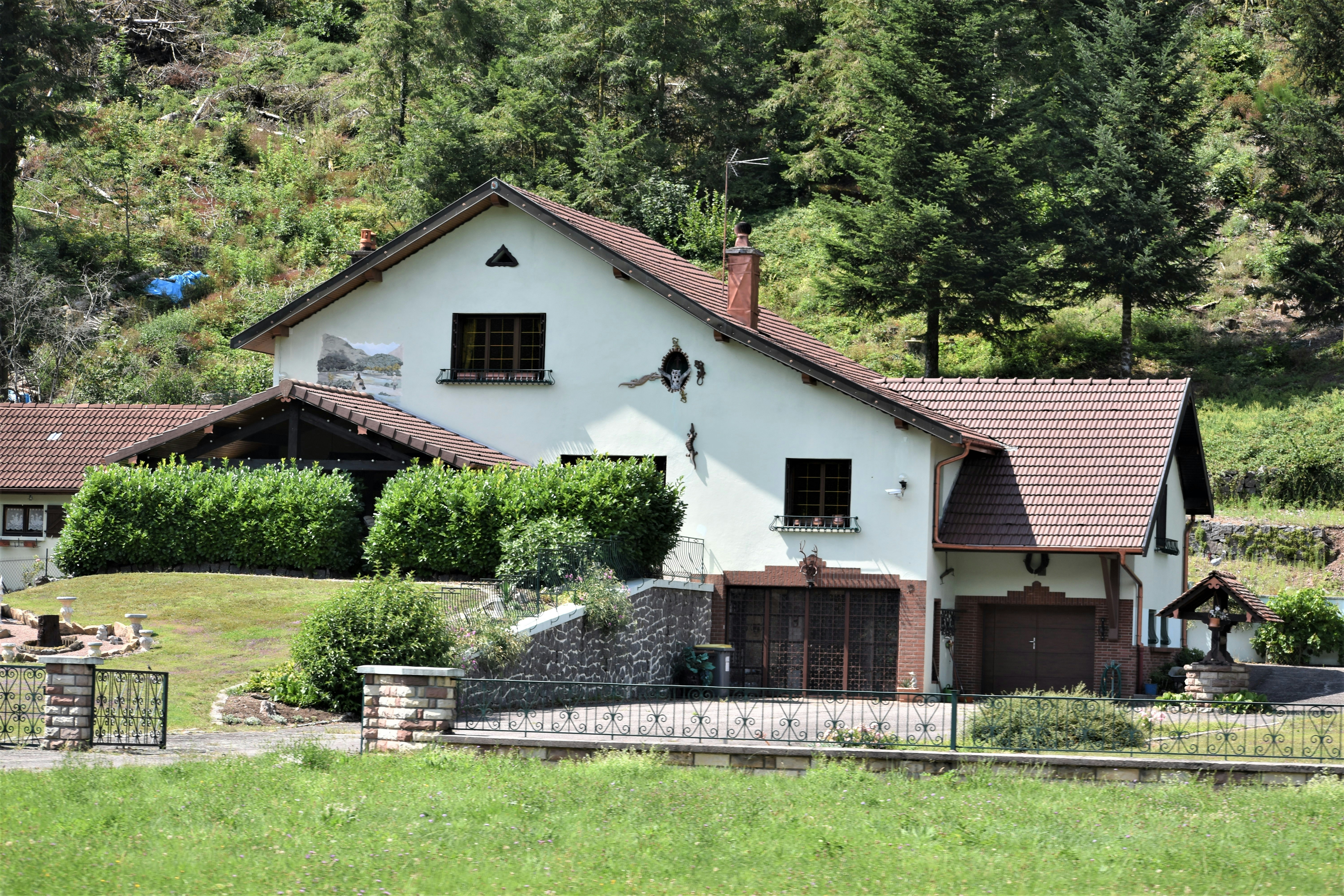 Village House | White house with brown roof and garage doors.