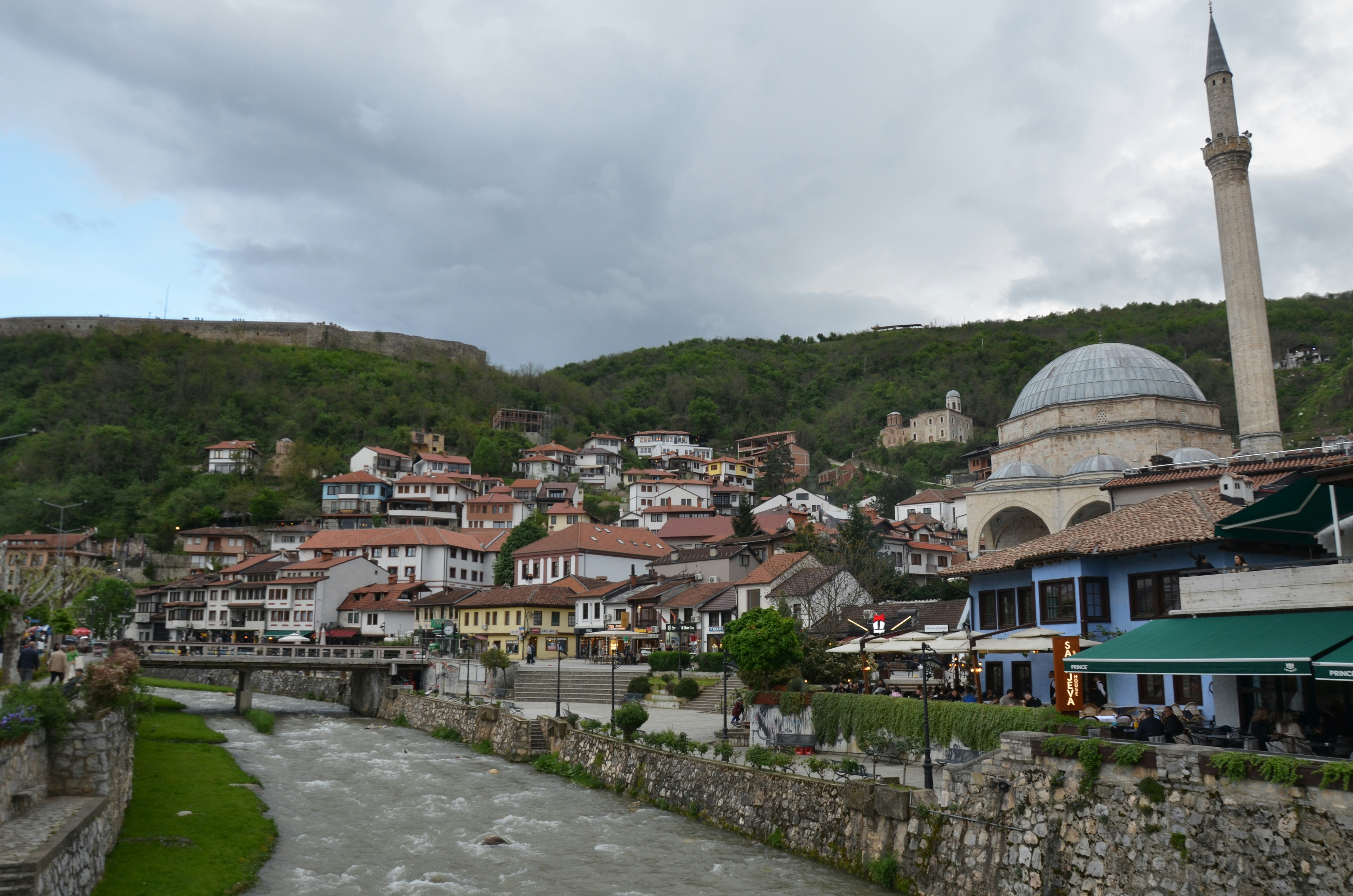 River flows through a historic city with mosque and fortress.