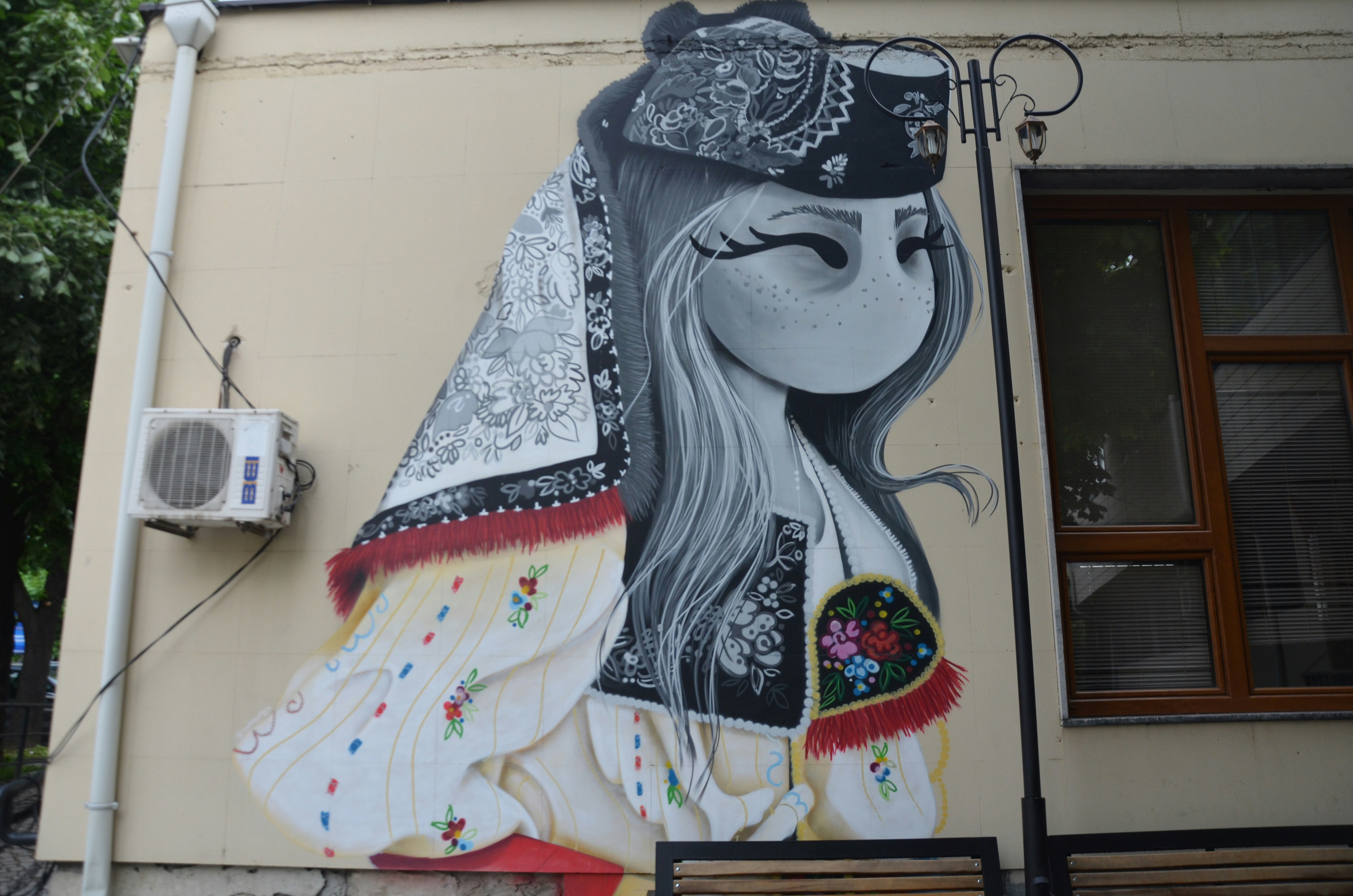 A vibrant mural depicting a woman in traditional attire adorned with intricate patterns and floral designs. The artwork beautifully blends cultural elements with modern artistic expression.