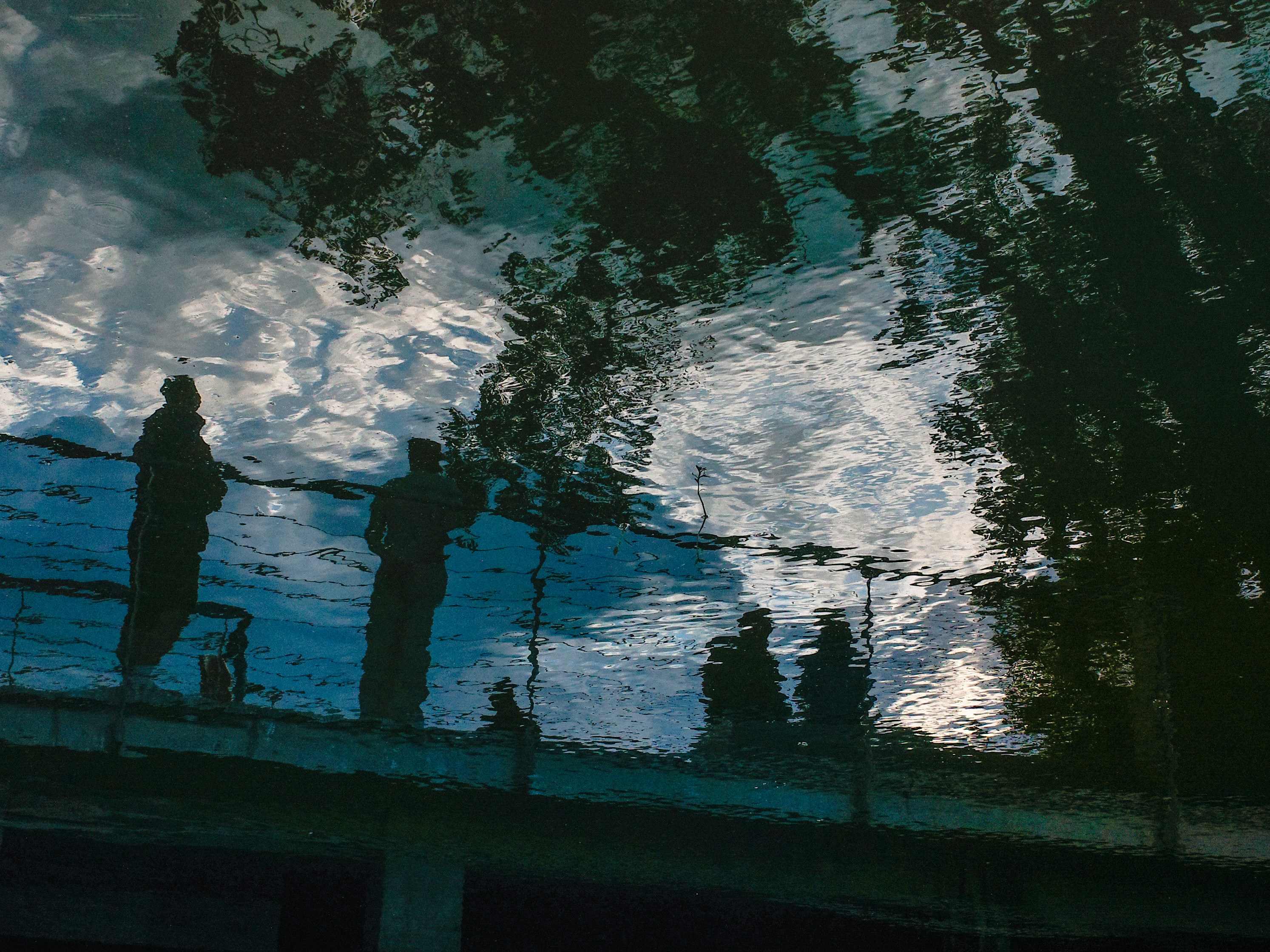 Silhouettes of people reflected in rippling water