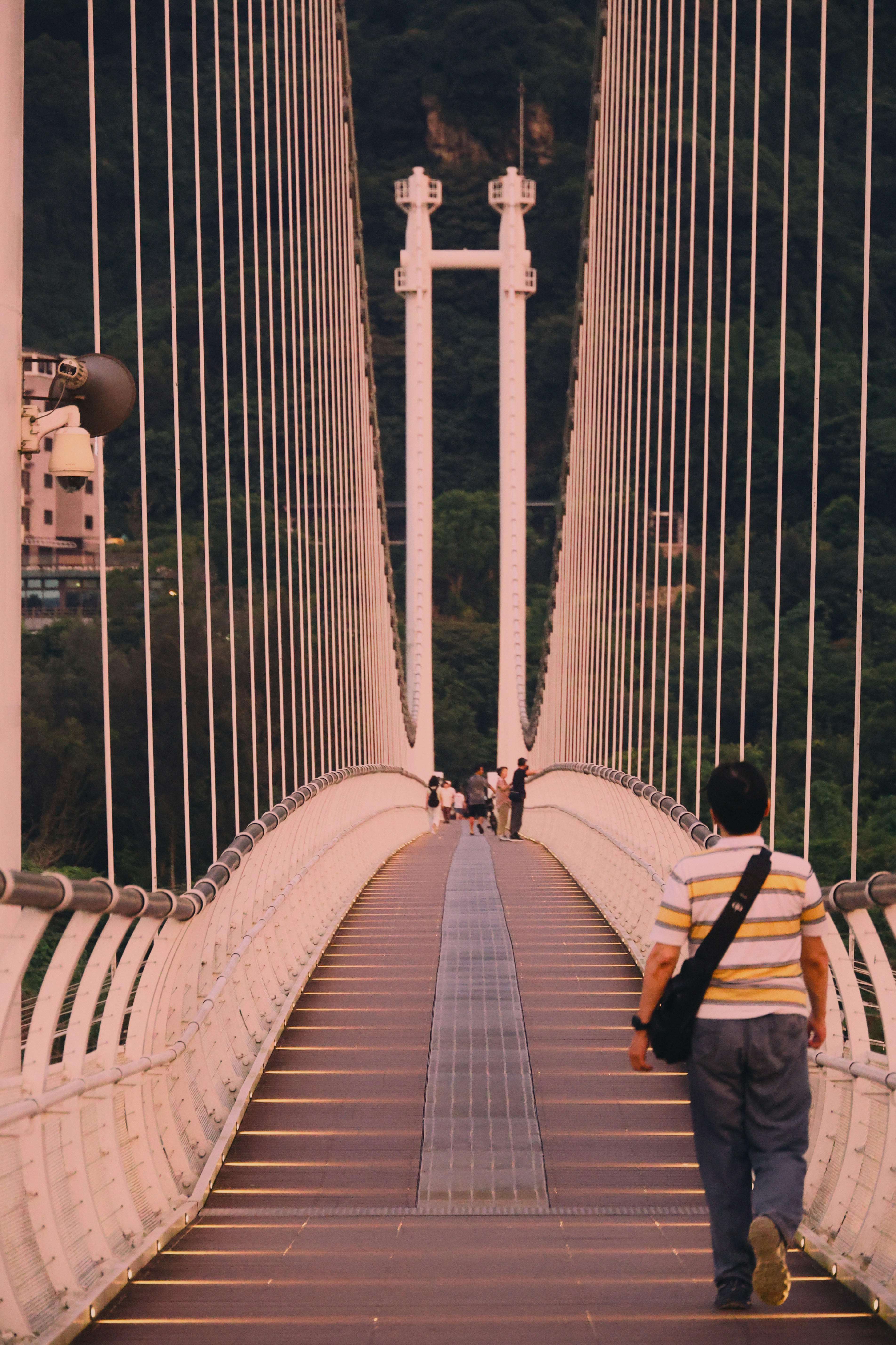 Man walking on a suspension bridge with people ahead