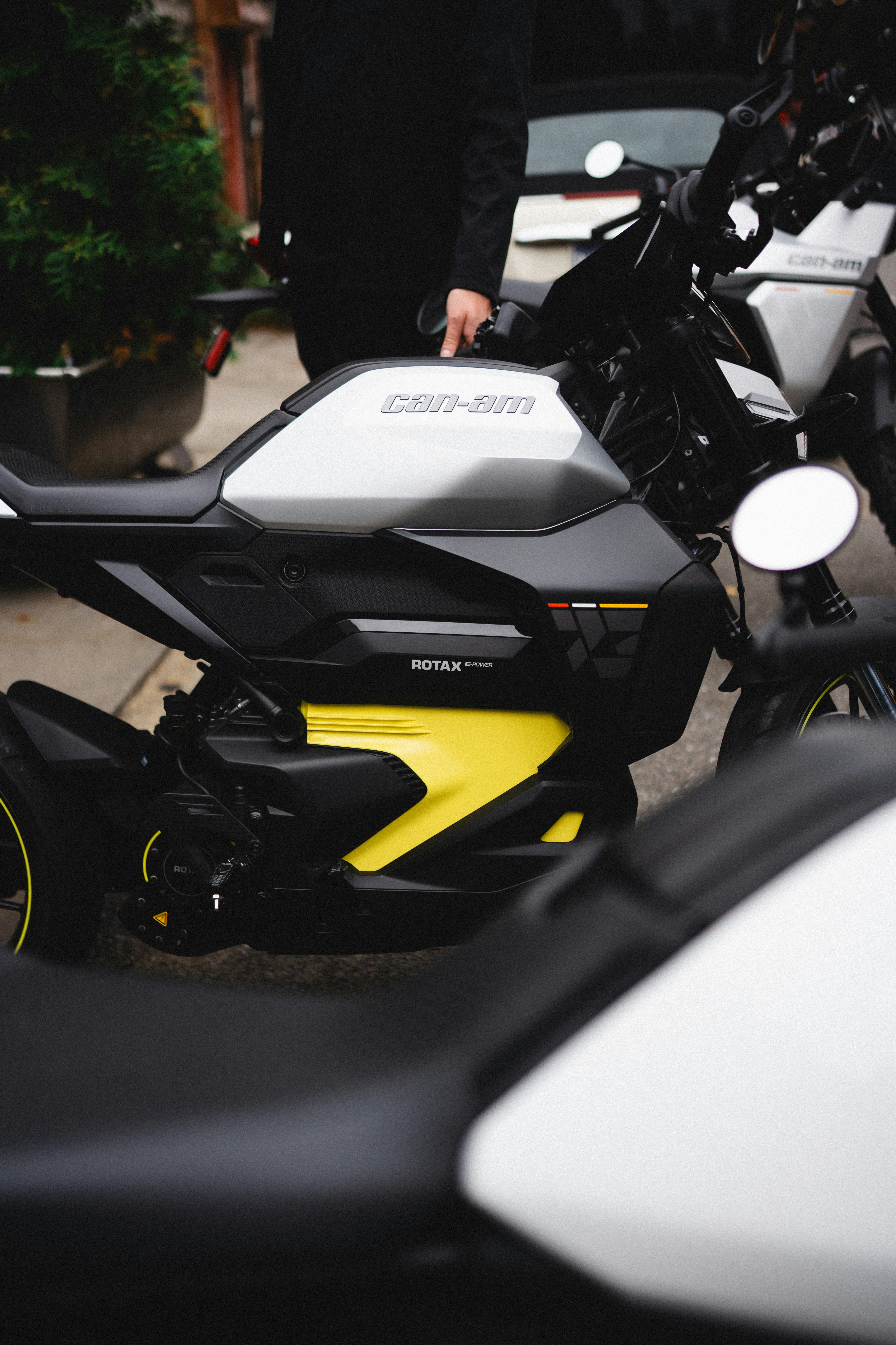 A sleek Can-Am motorcycle showcased against an urban backdrop, highlighting its modern design and vibrant yellow accents.