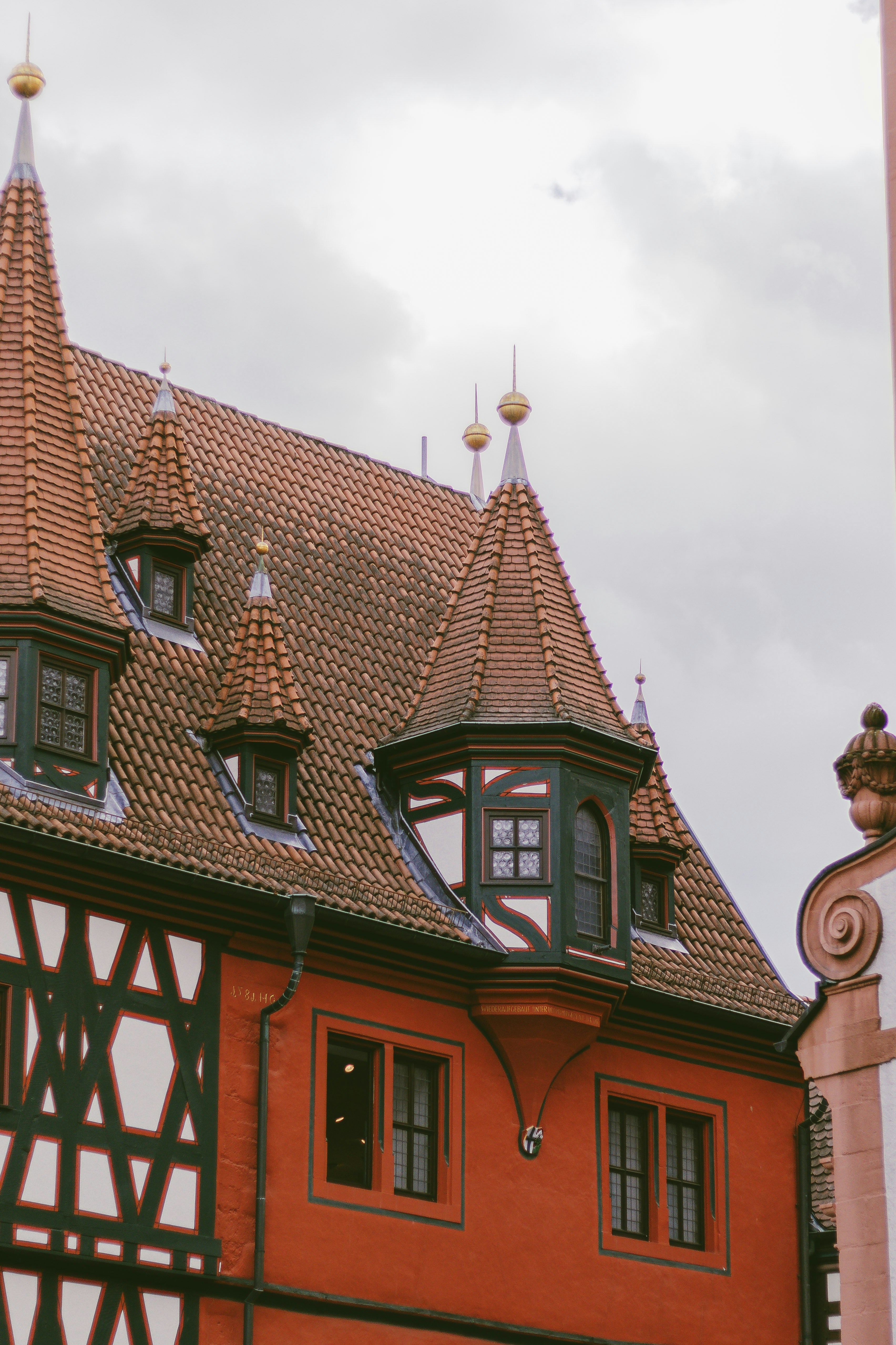 Intricate timber-framed building with distinctive red walls and ornate roof details, showcasing traditional architectural style.