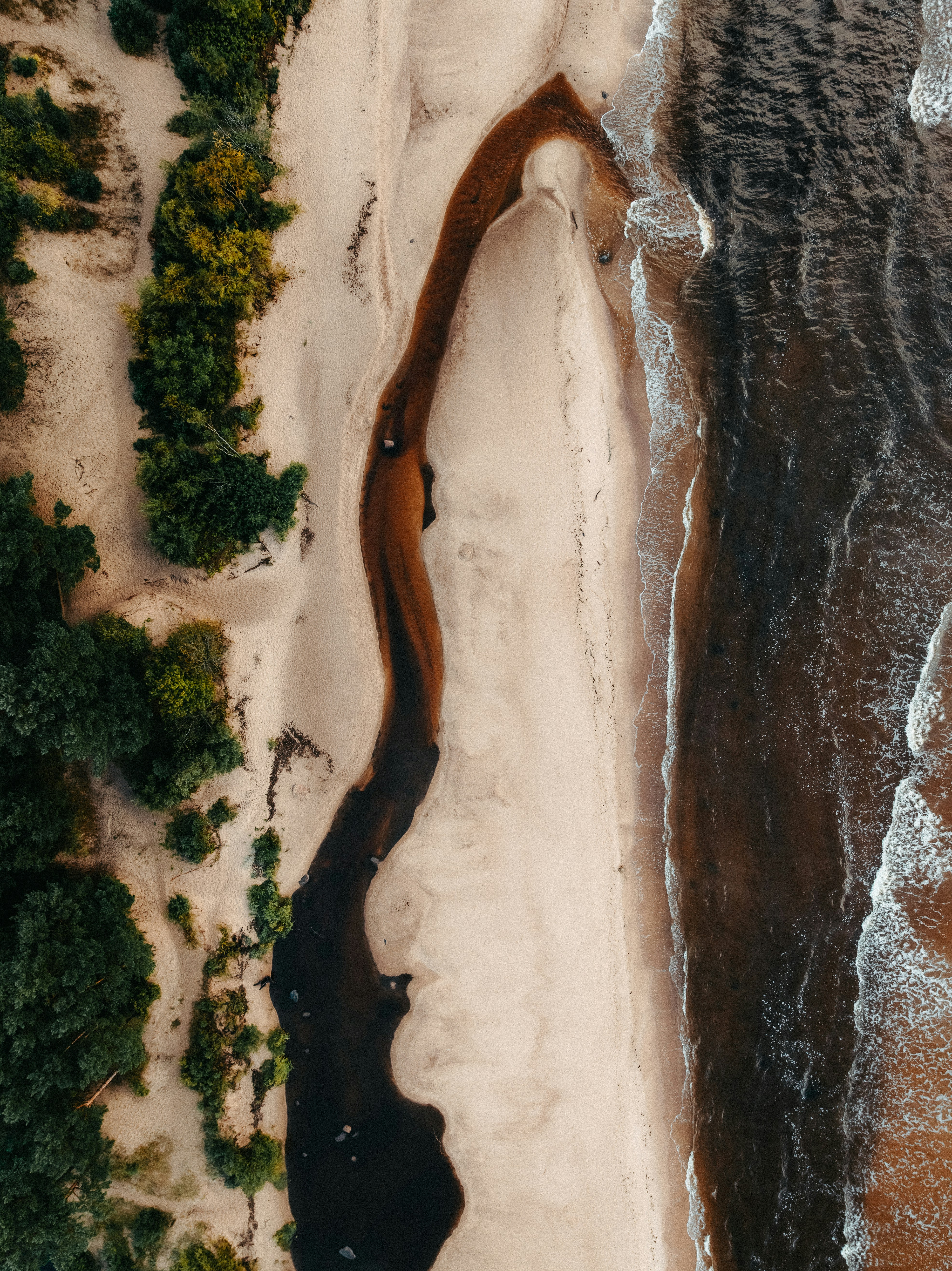 Aerial view of a river flowing into the ocean on a sandy beach. photo ...