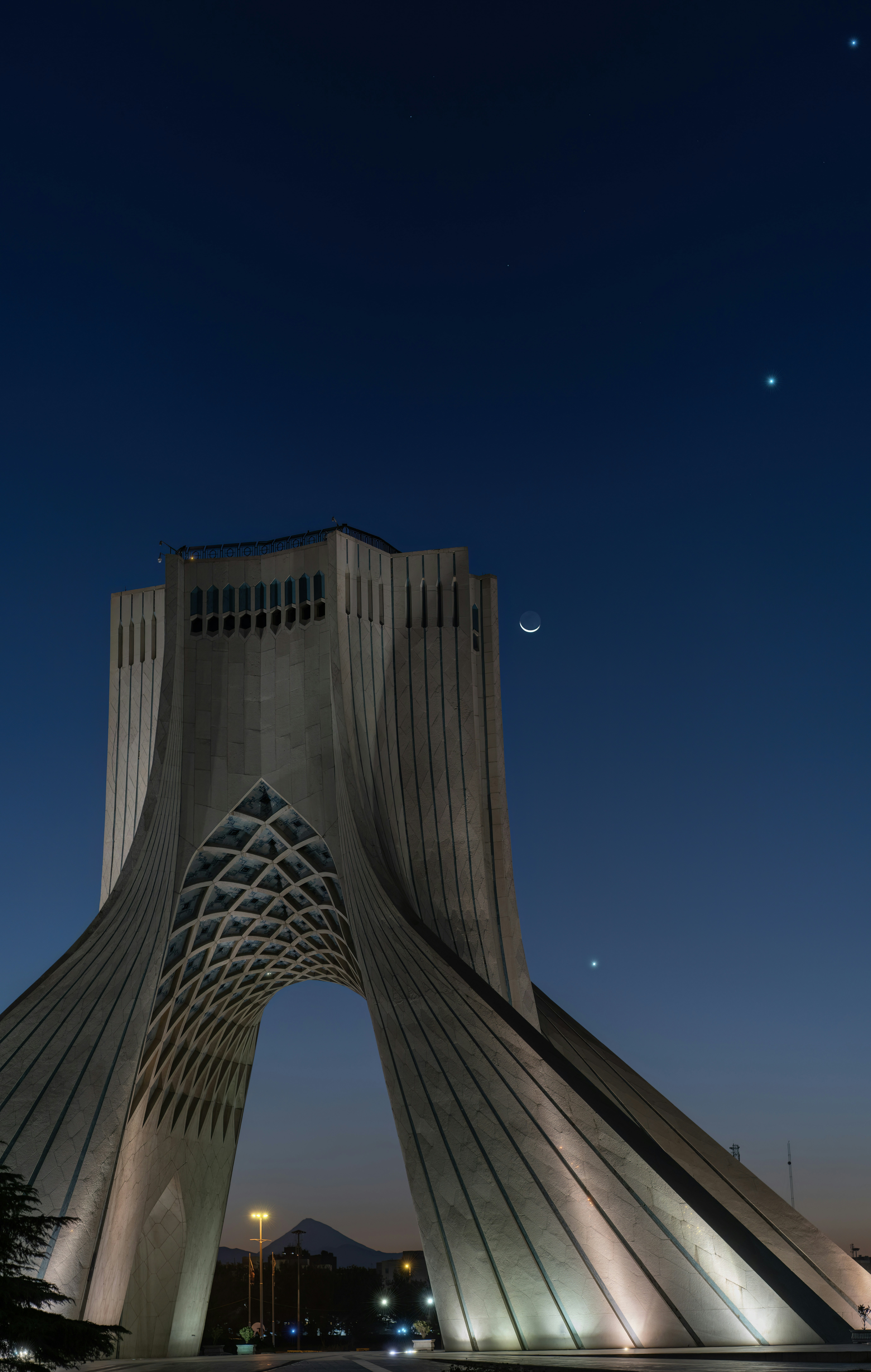 he Moon, Jupiter, Venus, and Mercury — the four brightest objects in the night sky — align in the early morning sky, Tehran, Iran. The Azadi Tower ("Freedom Tower"), also known as the Shahyad Tower ( "Shah's Memorial Tower"), is a monument on Azadi Square in Tehran, Iran. It is one of the landmarks of Tehran, marking the west entrance to the city, and is part of the Azadi Cultural Complex, which also includes an underground museum. | Iconic tower illuminated against a twilight sky.